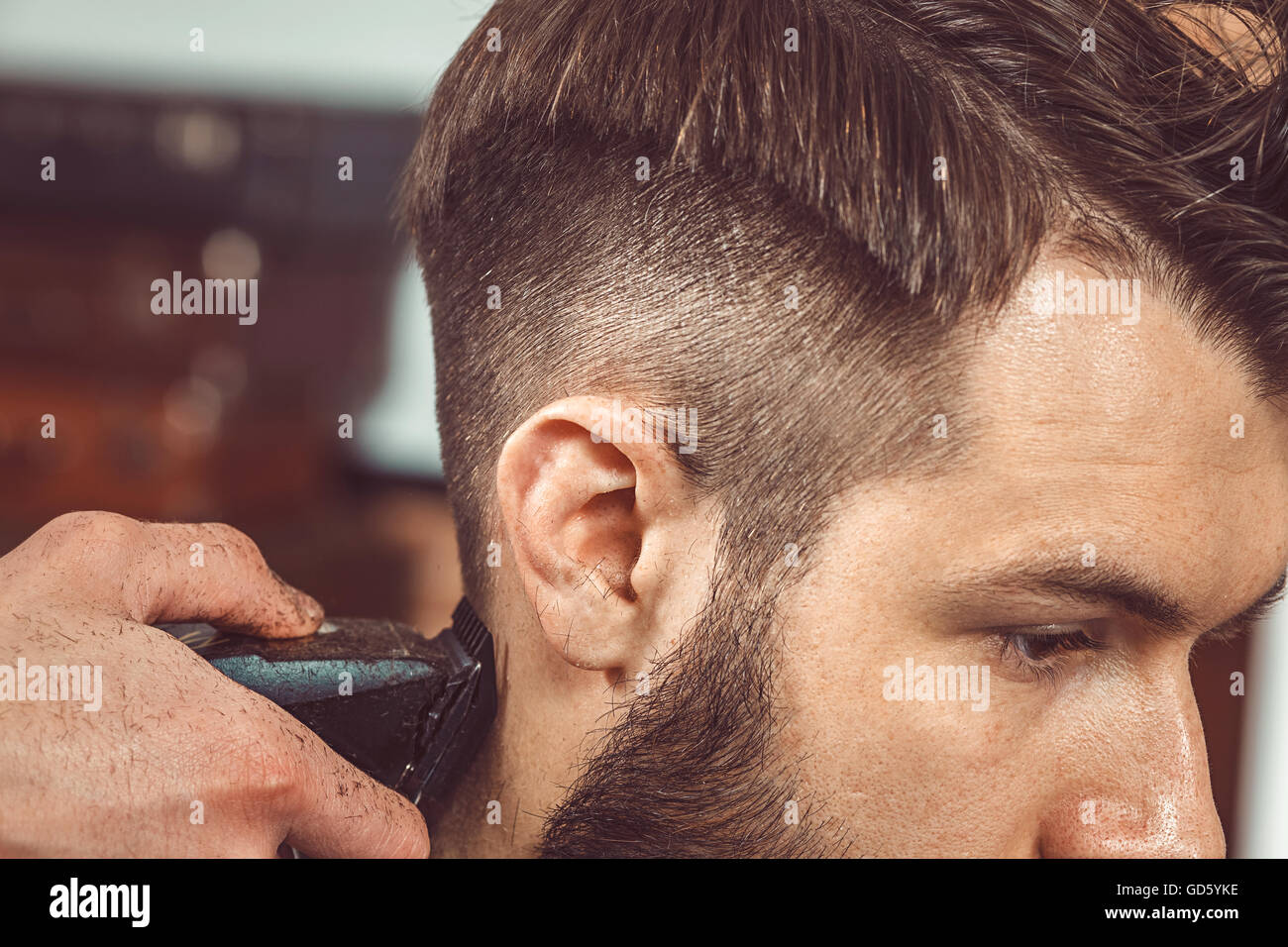 The hands of young barber making haircut to attractive man in ...