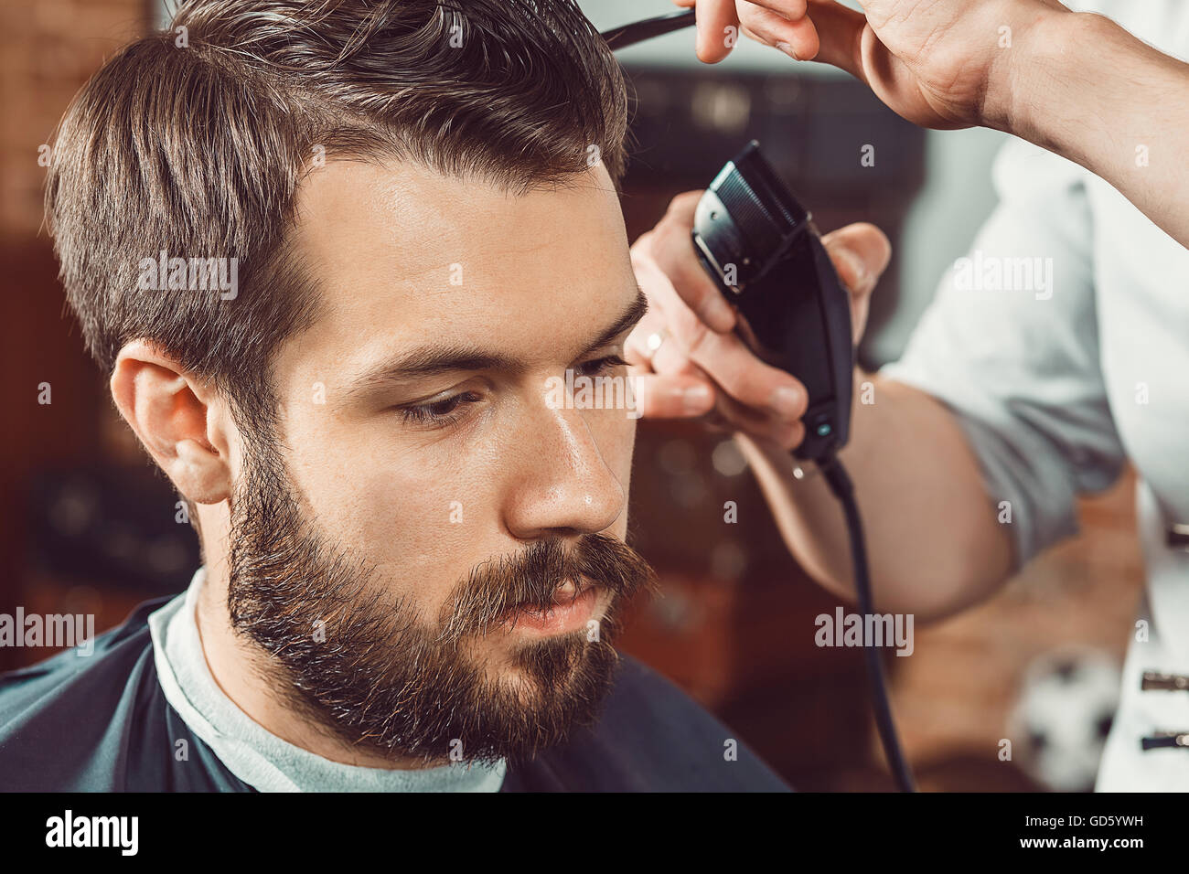The hands of young barber making haircut attractive man in barbershop ...