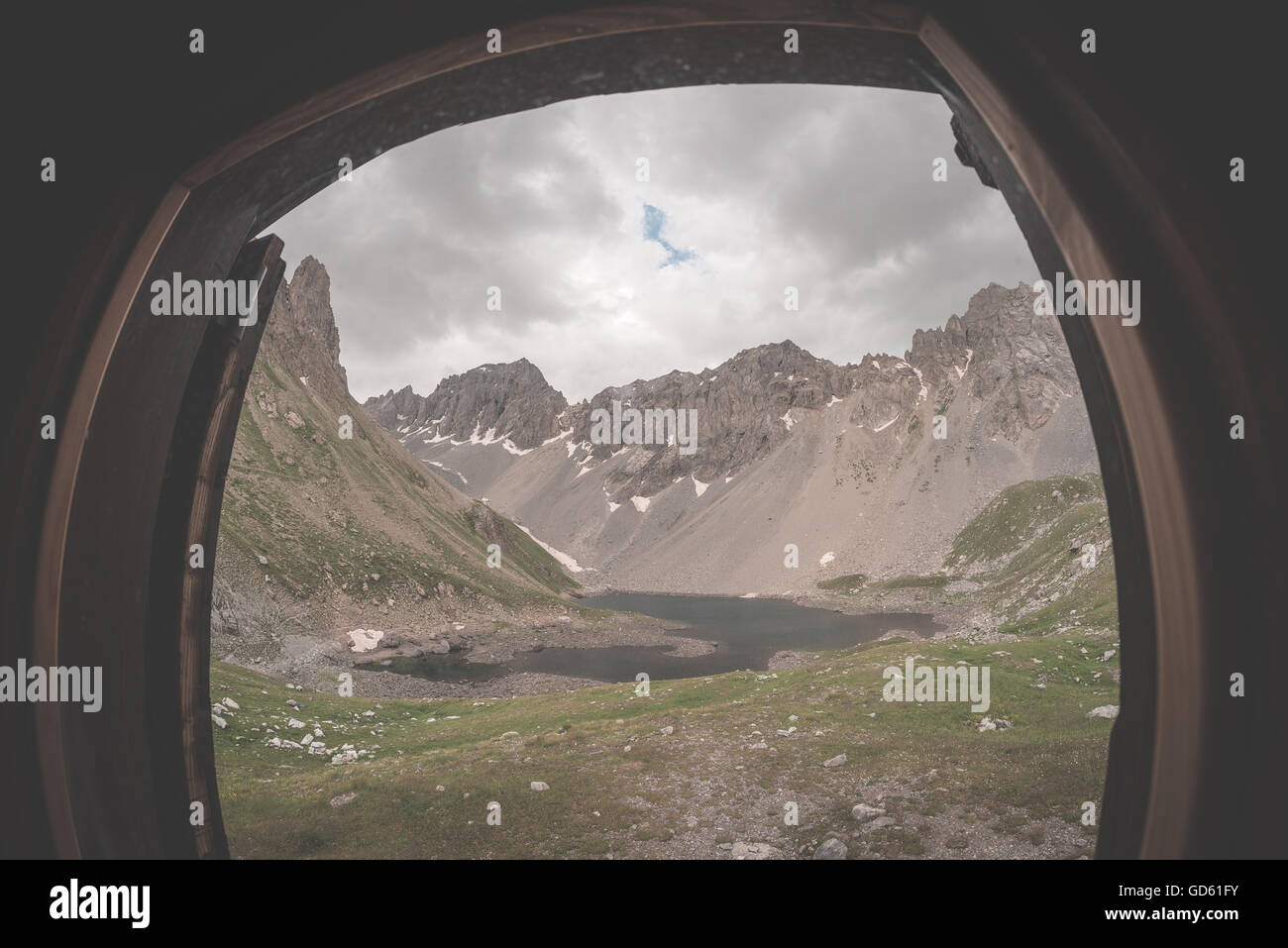 Looking through window at expansive panorama of alpine valley with lake ...