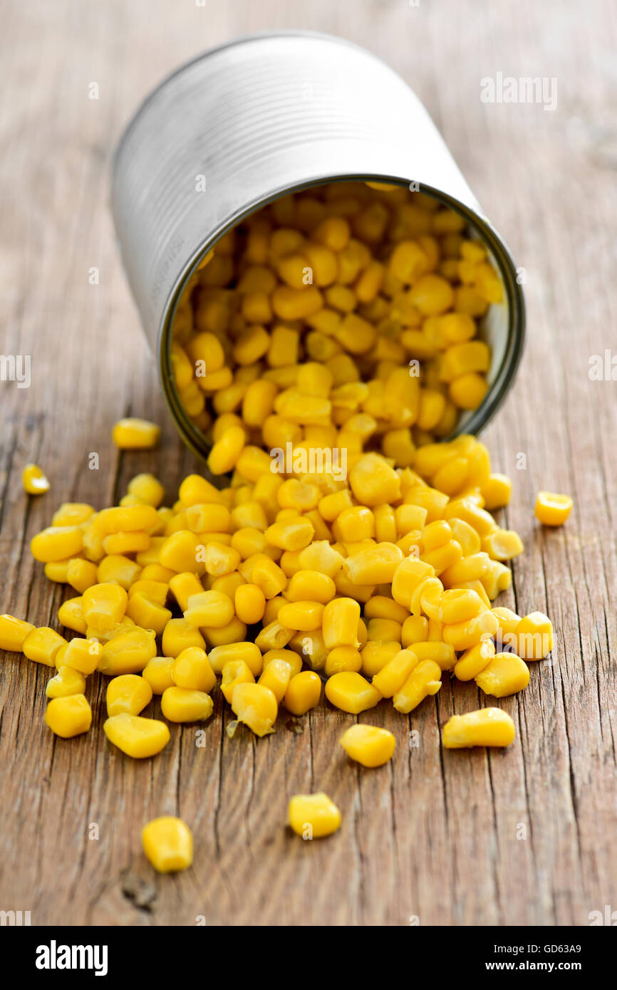 a pile of sweet corn from a can scattered over a rustic wooden surface ...