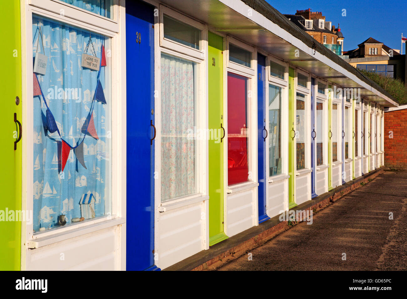 A row of joined beach huts with large glass windows on the east ...