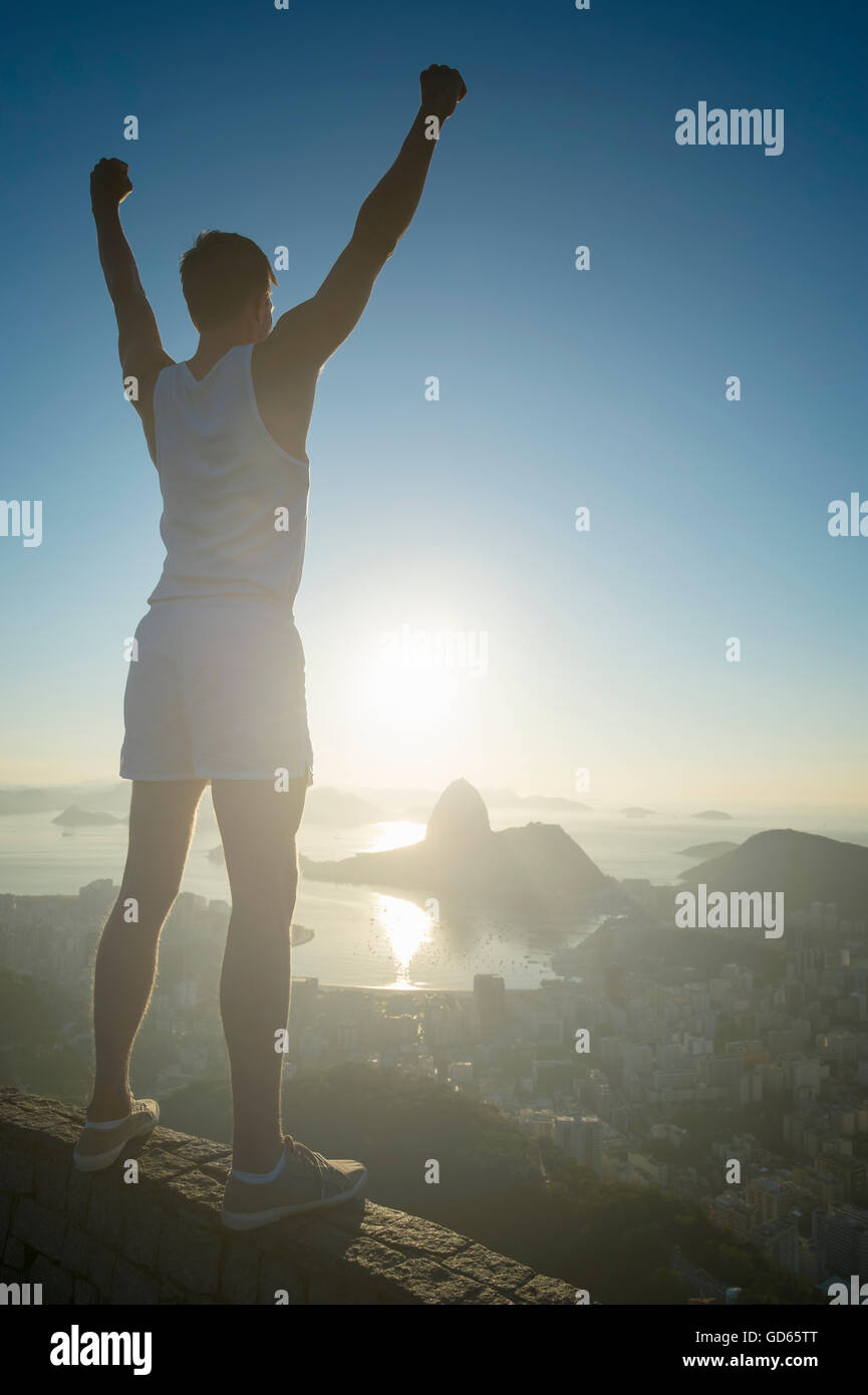 Silhouette of athlete standing with champion arms raised in front of ...