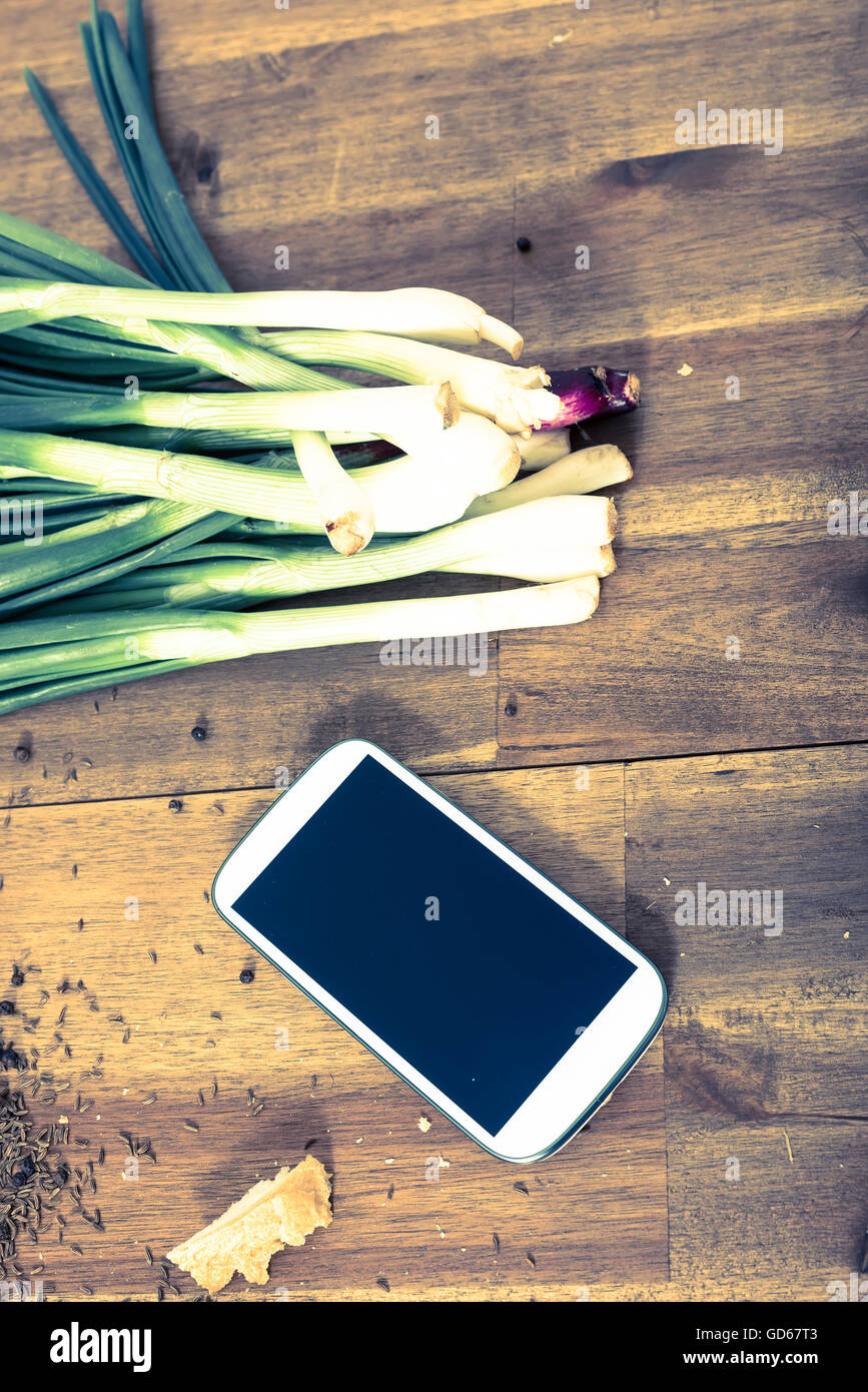 A smartphone lying in a natural kitchen with white bread, spices ...
