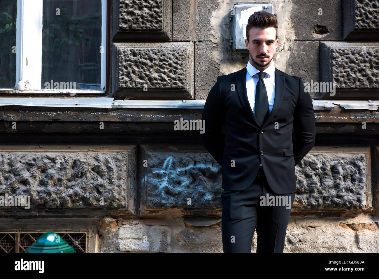 Portrait of a young businessman leaning against the wall outside Stock ...