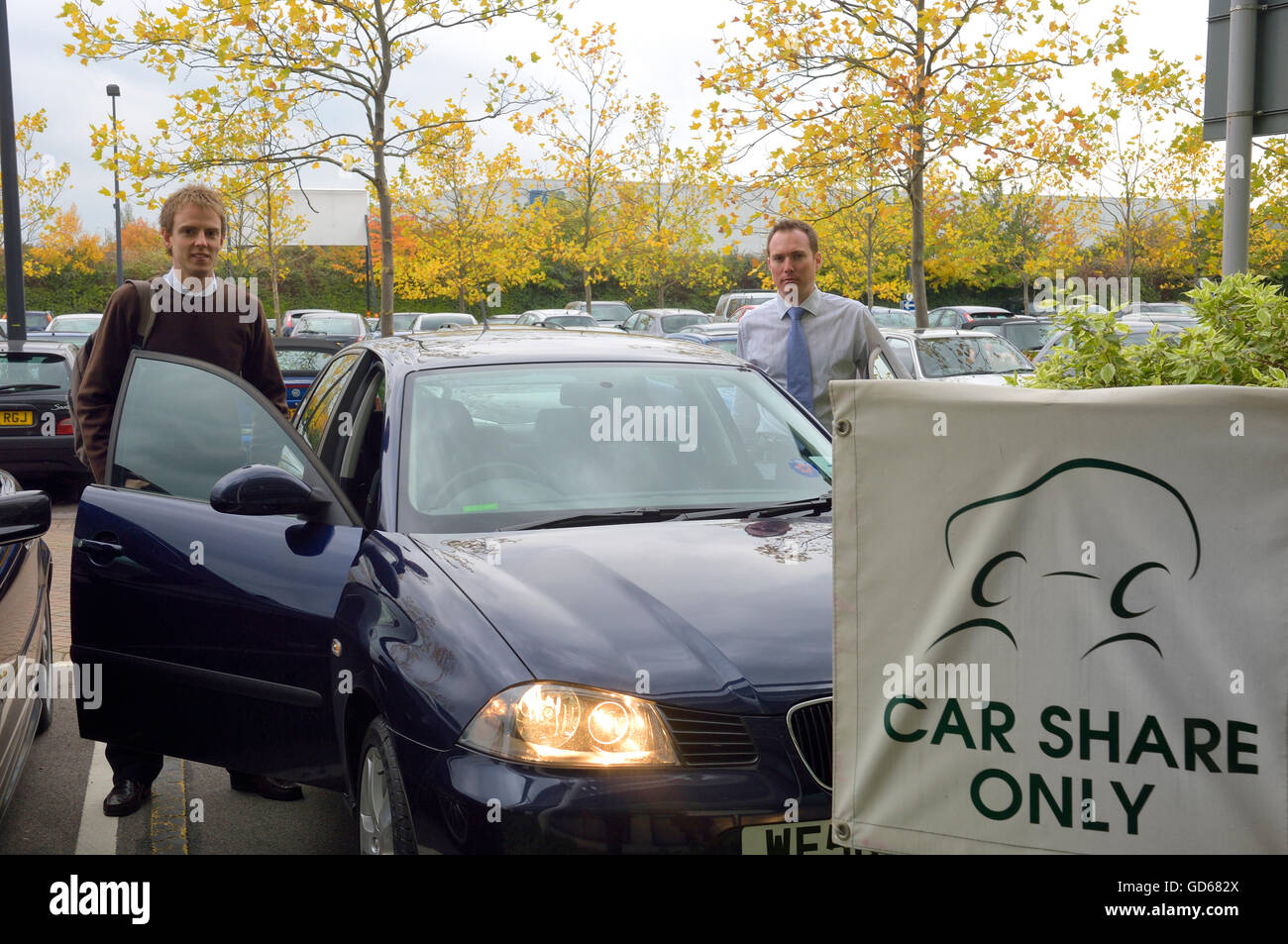 Two car sharers getting into a car at their workplace car park. England ...