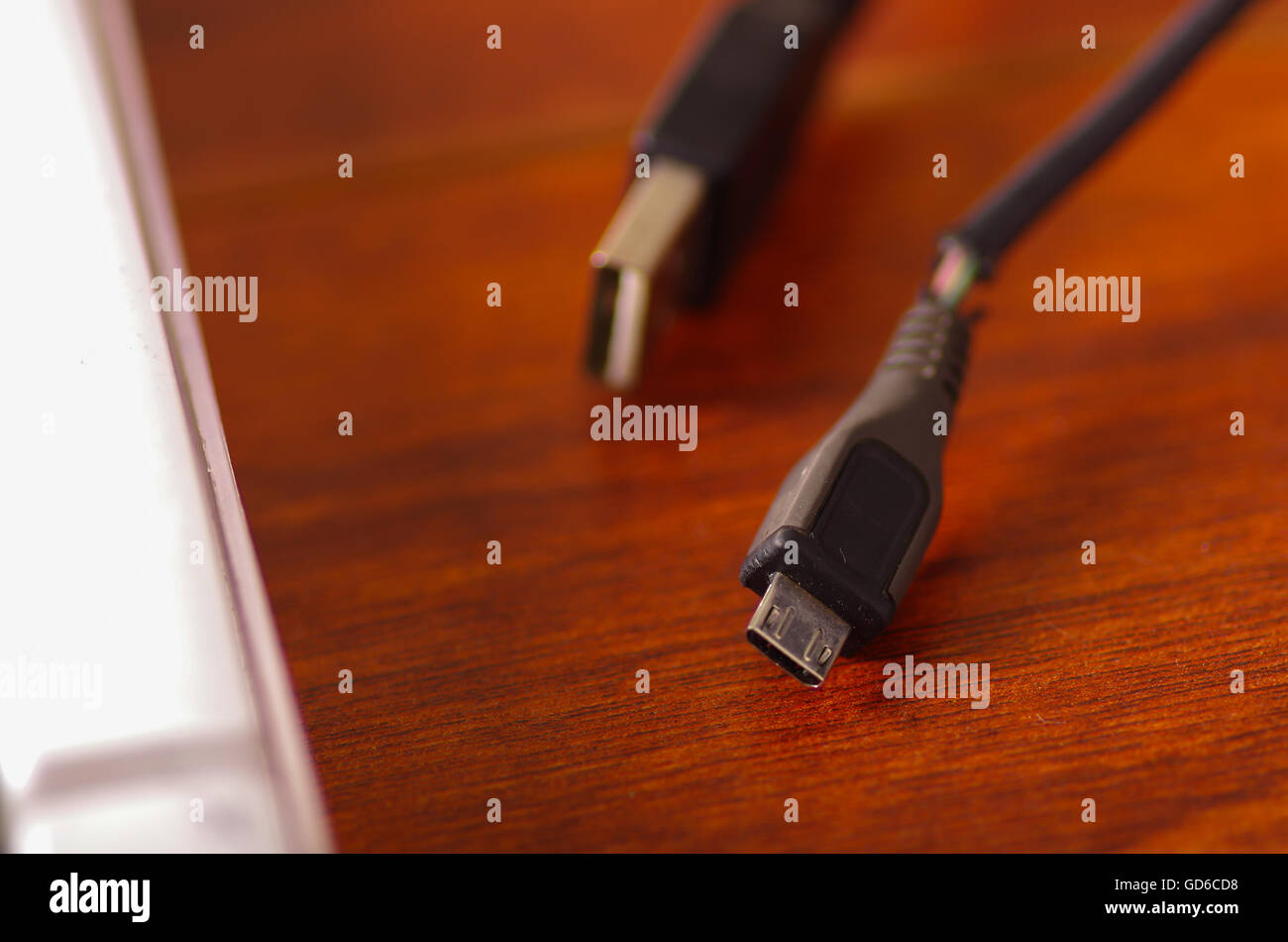 Broken usb mobile charger cable lying on wooden surface, part of ...