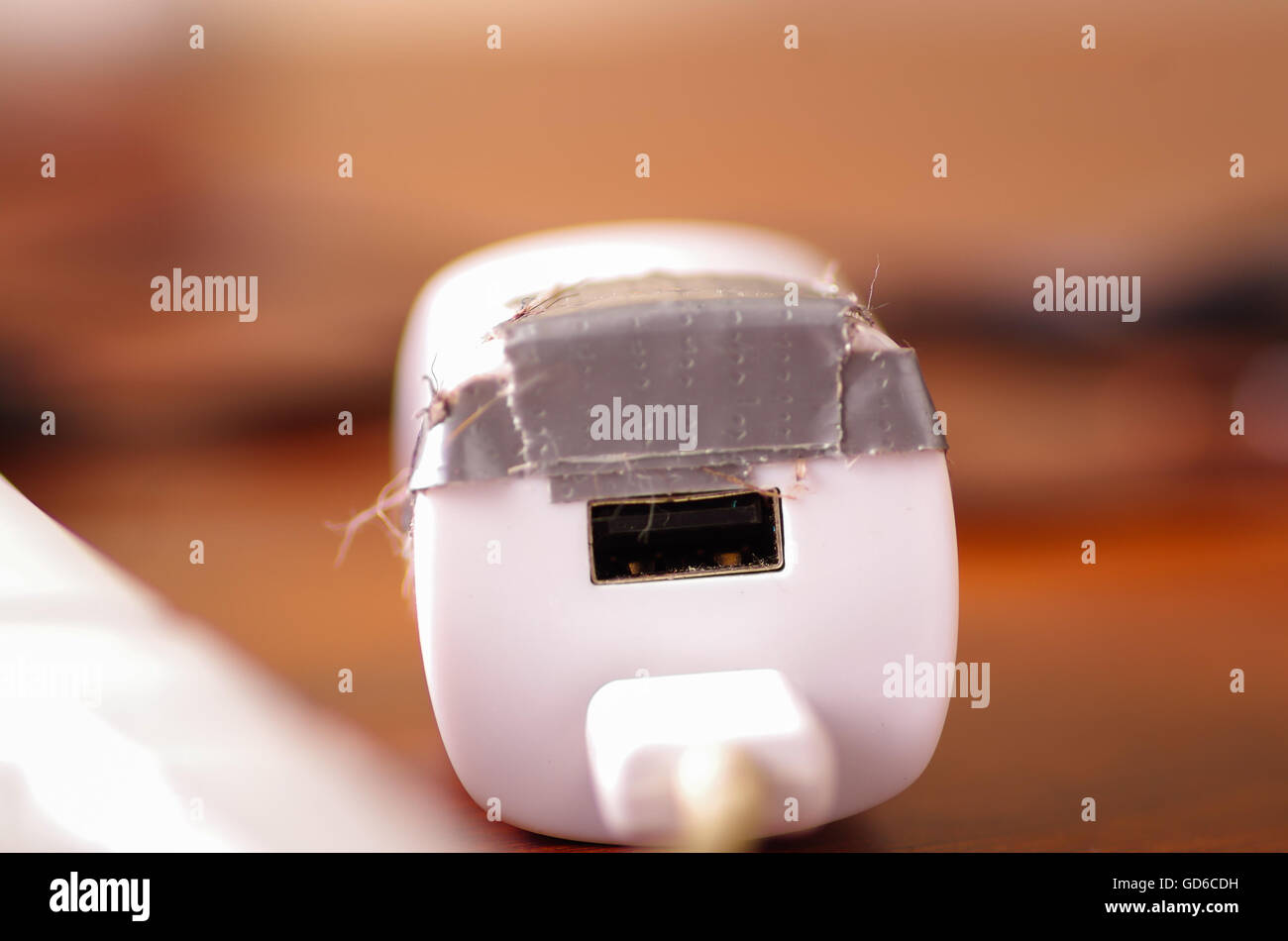 Broken usb mobile charger cable and block lying on wooden surface ...