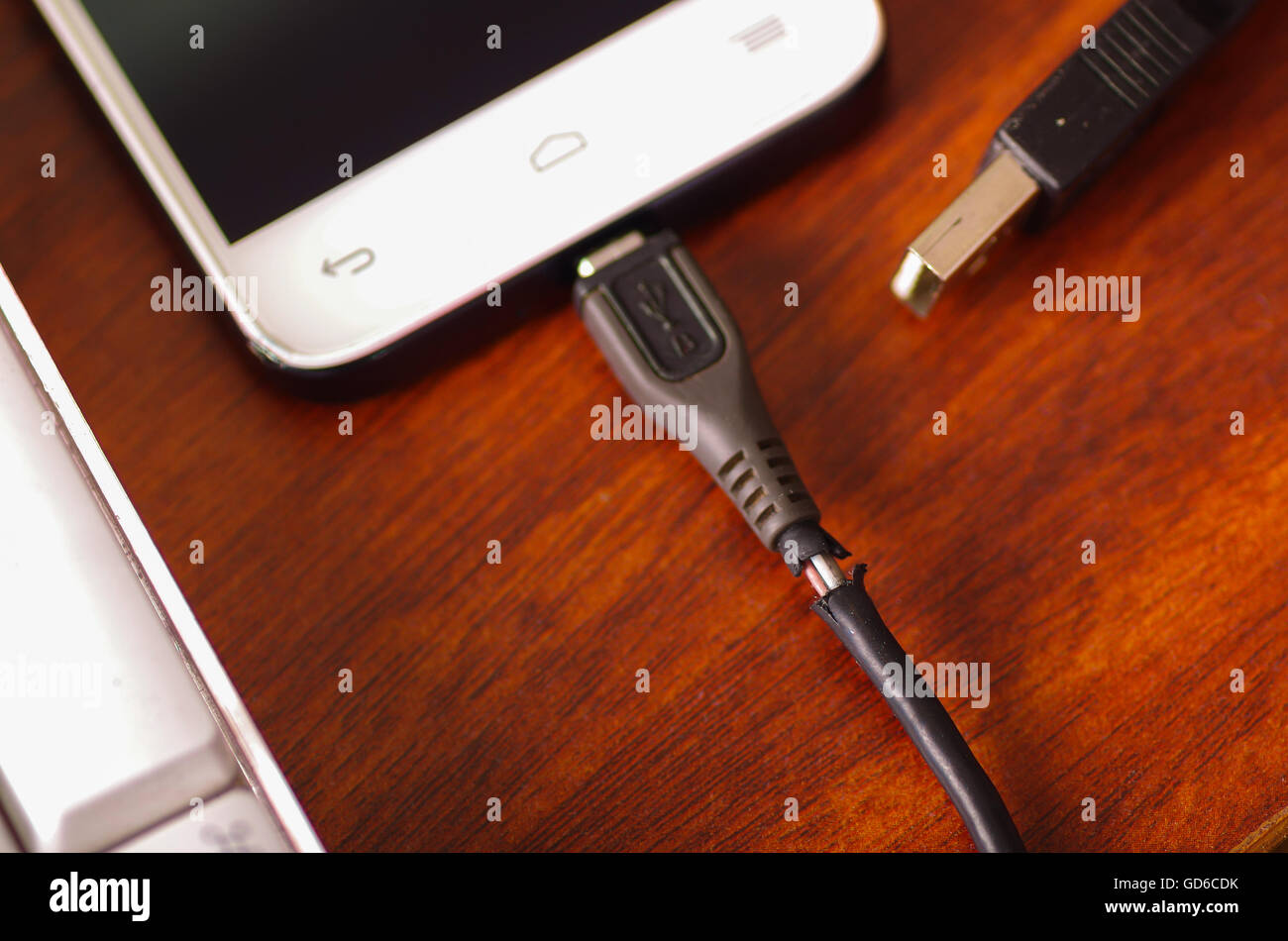 Broken usb mobile charger cable connected into smartphone lying on ...