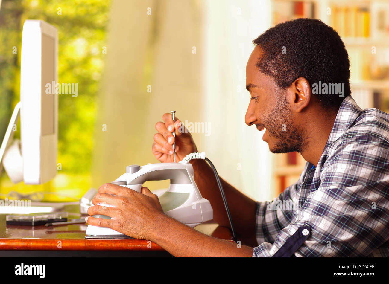 Man standing by desk repairing iron machine using screwdriver, window ...