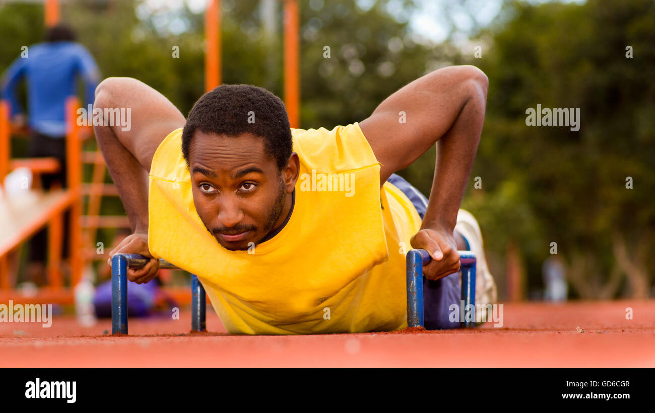 Man wearing yellow shirt doing push-ups at outdoors training facility ...