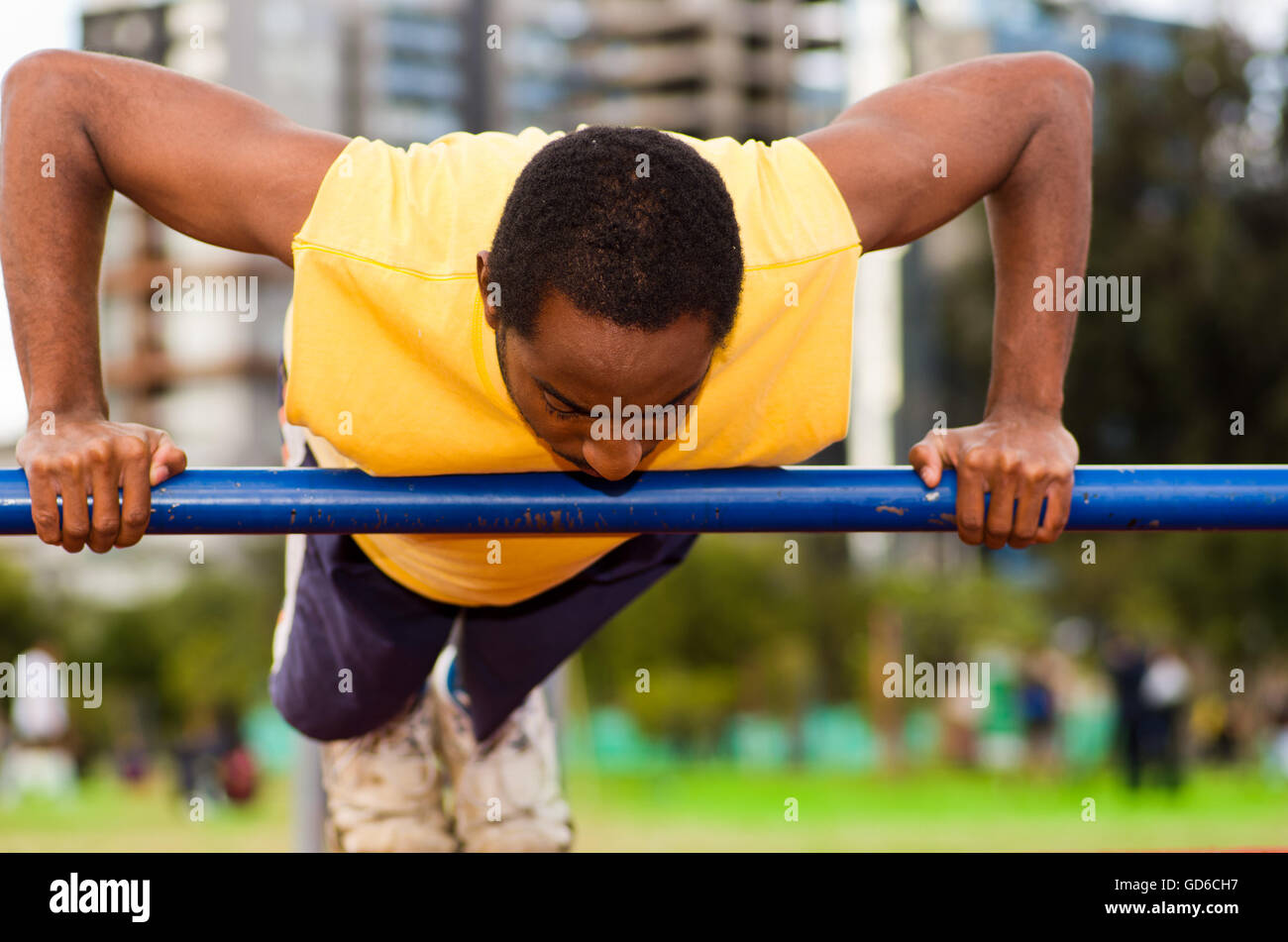 Man wearing yellow shirt and blue shorts doing static strength ...