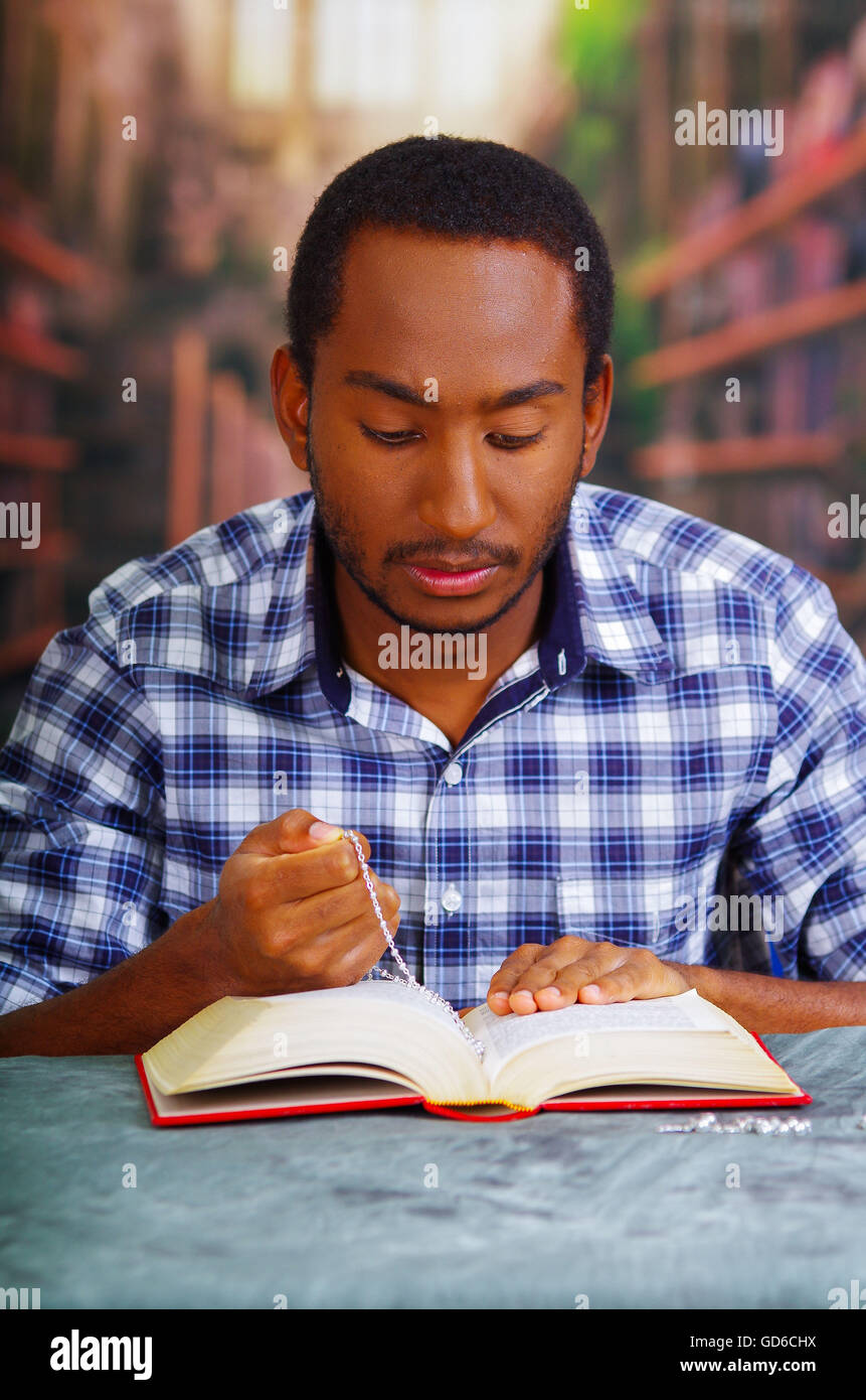Religious man sitting while holding rosary, praying and reading from ...