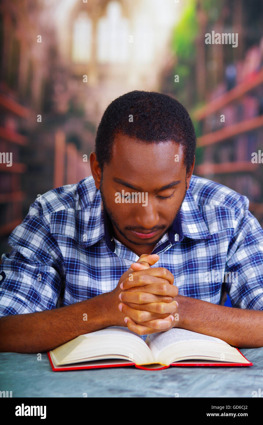 Religious man sitting while holding rosary, praying and reading from ...