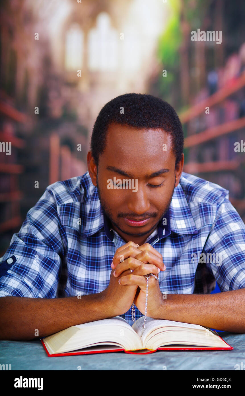Religious man sitting while holding rosary, praying and reading from ...