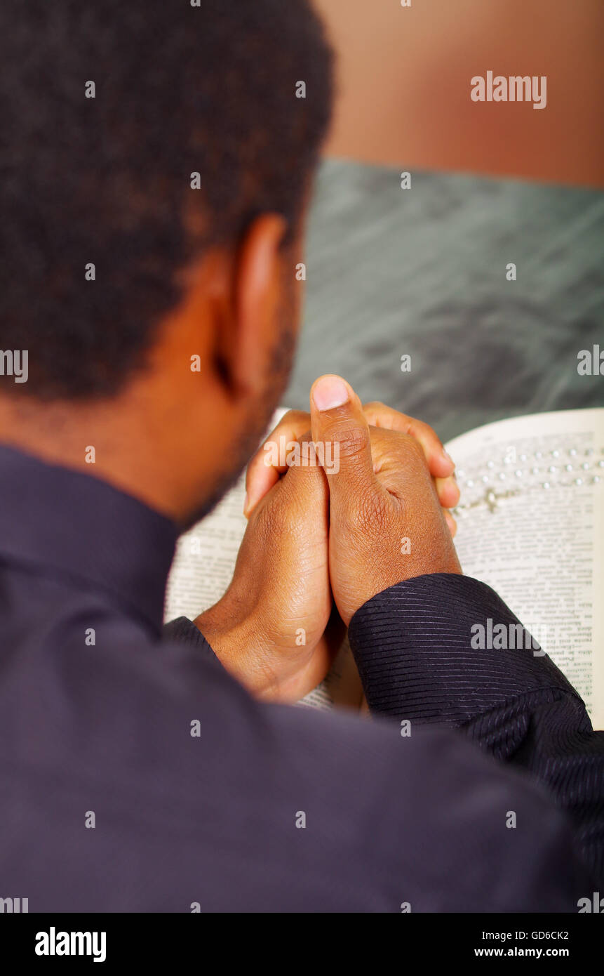 Man folding hands praying with open bible lying in front, seen from ...