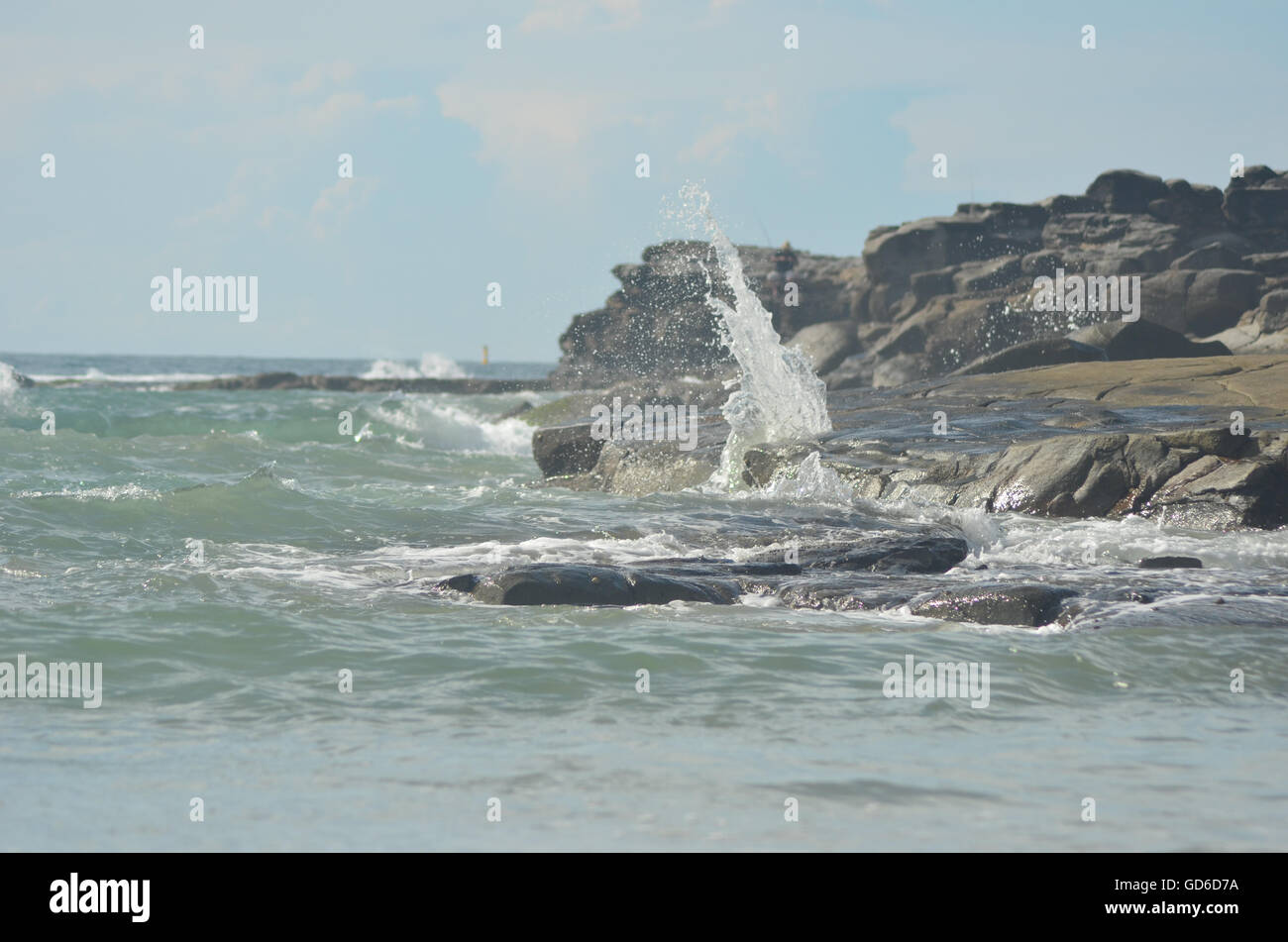 A wave breaking on rocks, with more rocks in the background Stock Photo ...