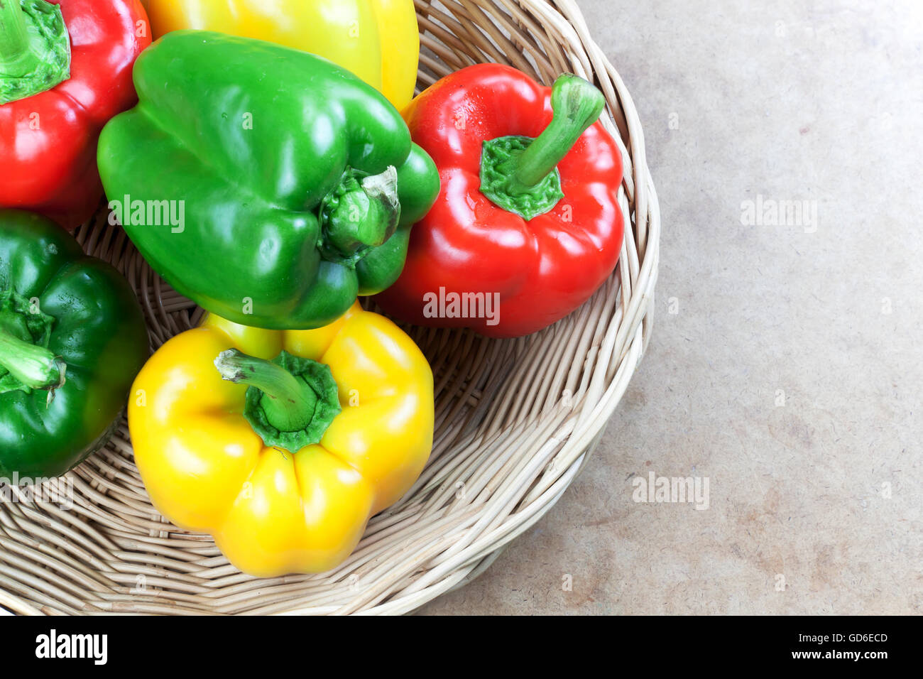 three color bell peppers in a basket on the table Stock Photo - Alamy