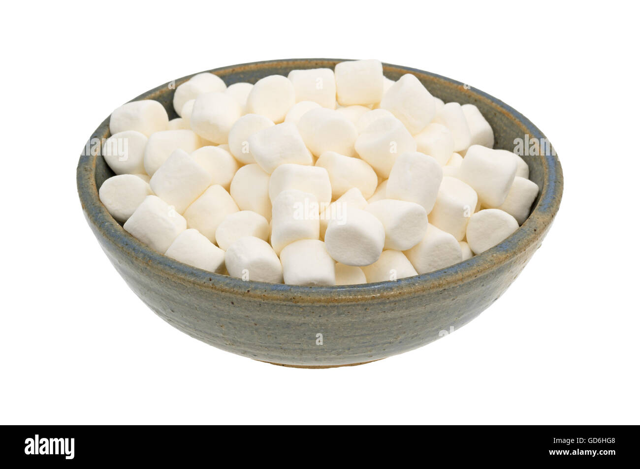 Small bite size marshmallows filling an old stoneware bowl isolated on ...