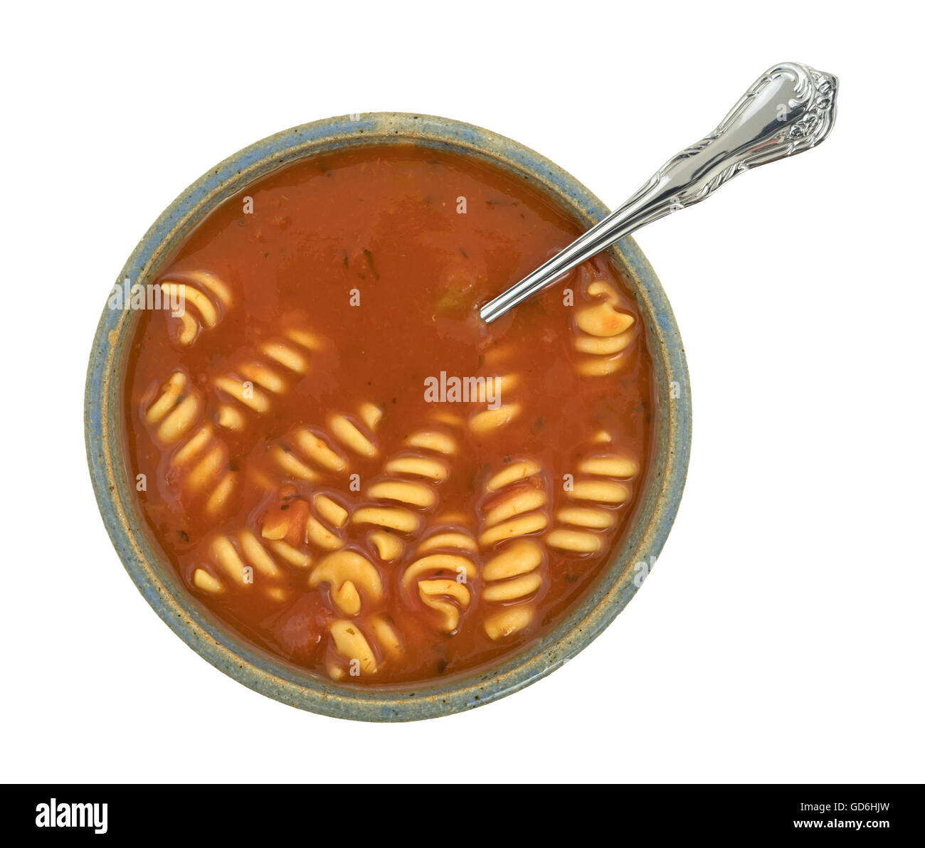 Rotini tomato soup in an old stoneware bowl with a spoon inserted into ...