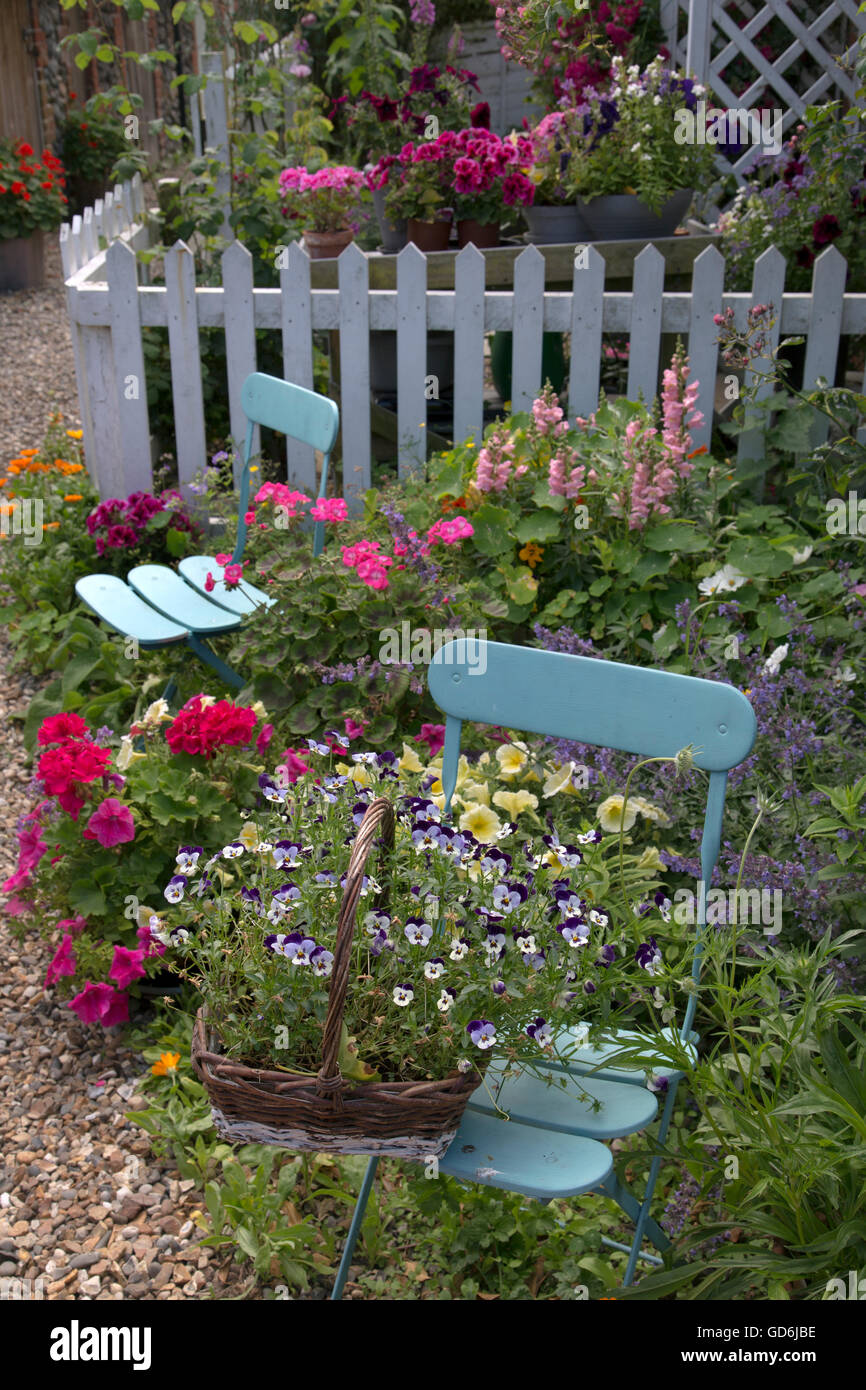 Cottage garden with container planting and blue chairs Stock Photo - Alamy