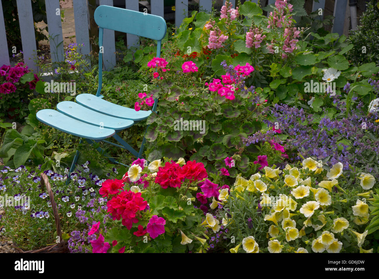 Cottage garden with container planting and blue chair Stock Photo - Alamy
