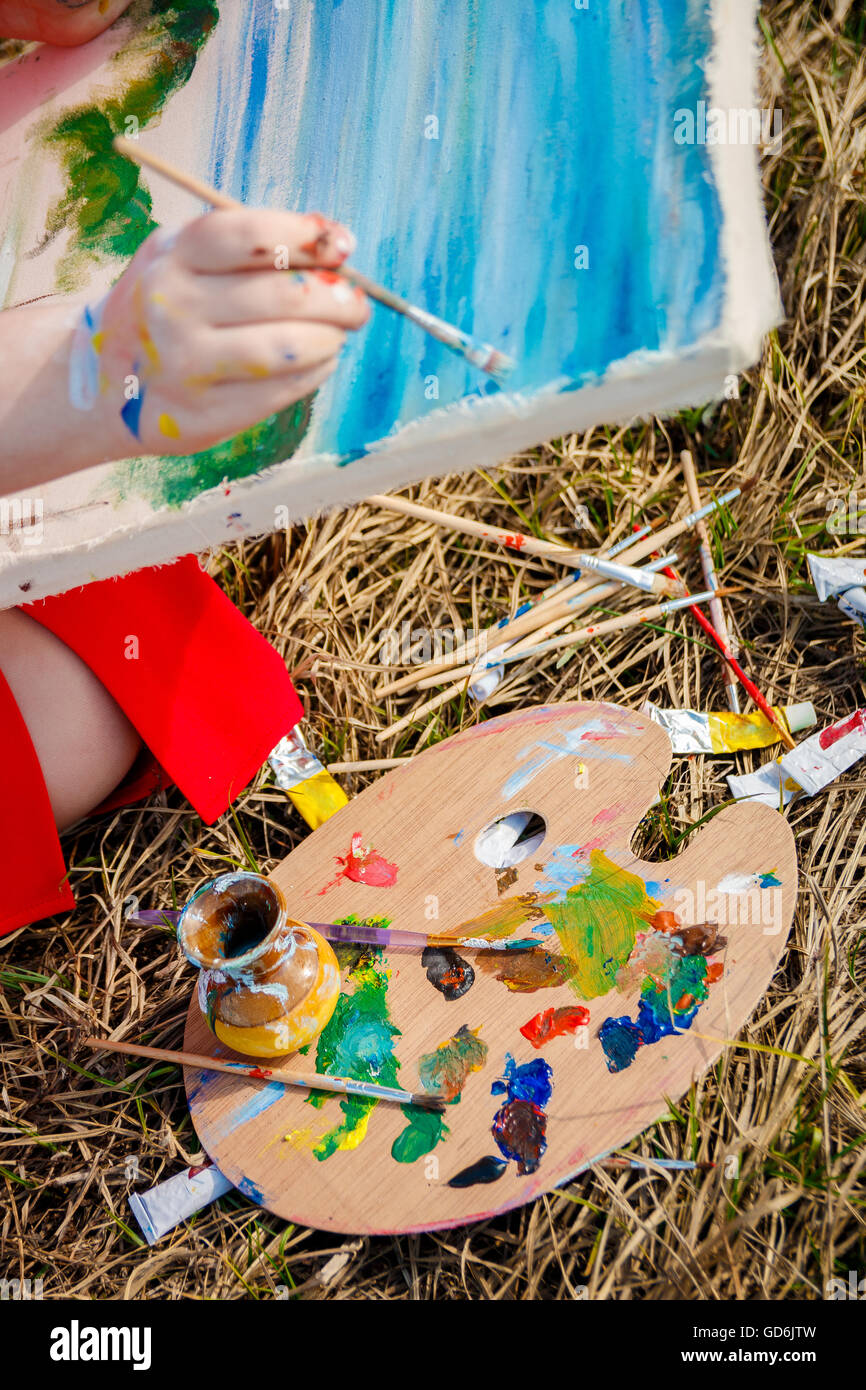 artist hand drawing the picture and Palette with paints and brushes on ...