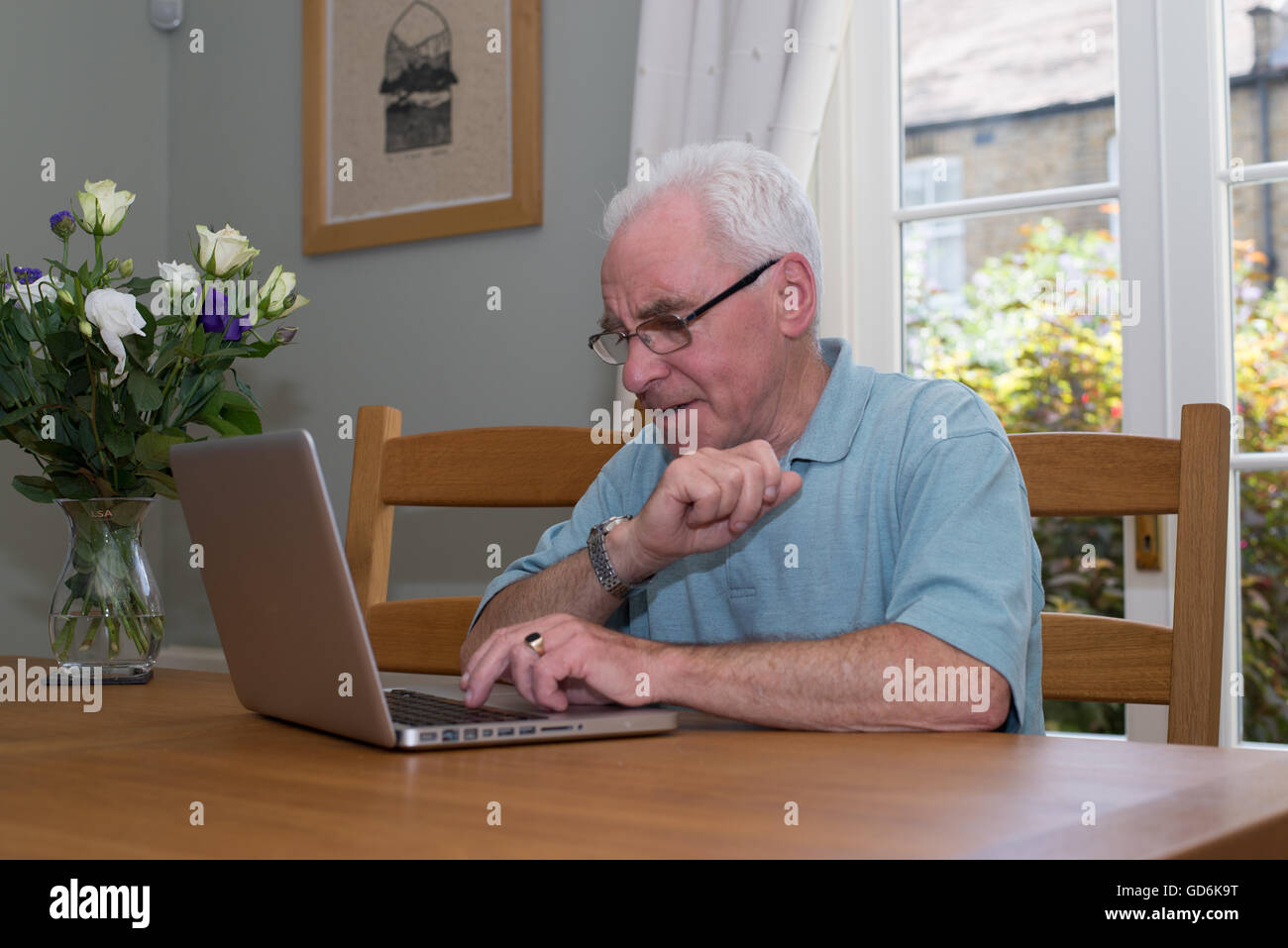 Old man sat down at a table using a laptop computer Stock Photo - Alamy