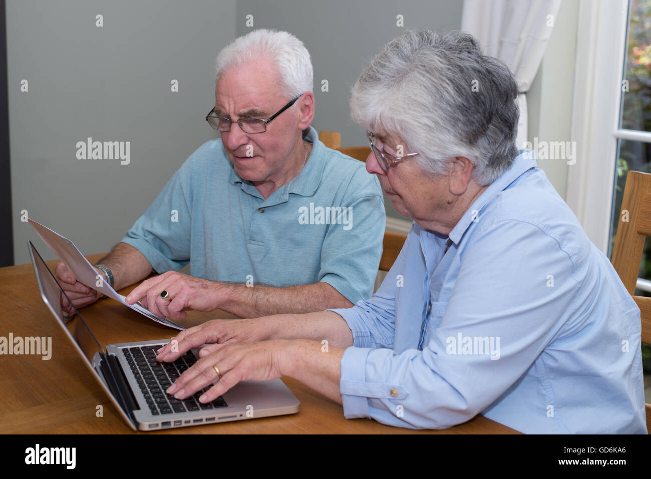 Old couple at home using laptop computer sat at the dining table Stock ...