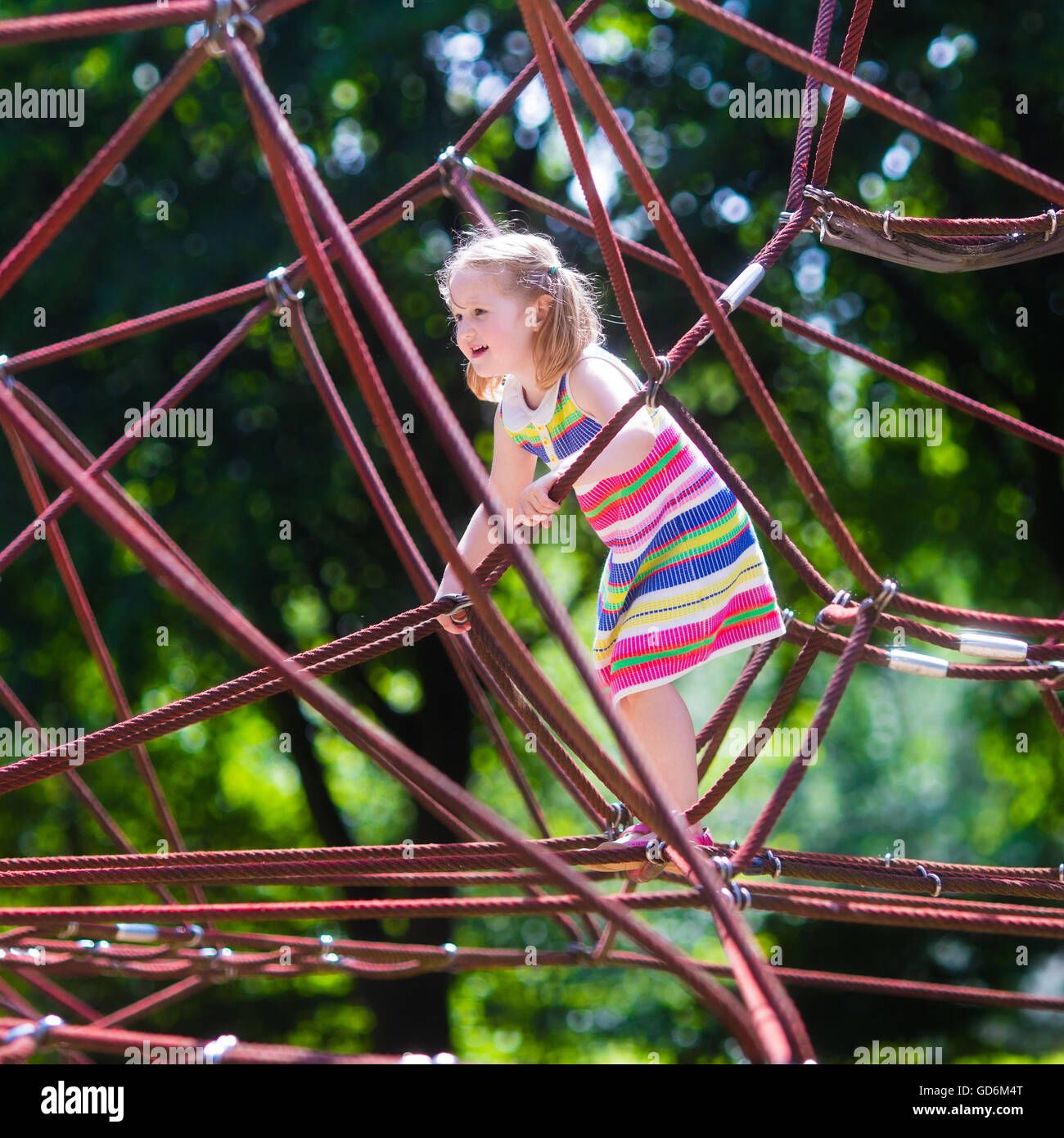 Active little child playing on climbing net and jumping on trampoline ...