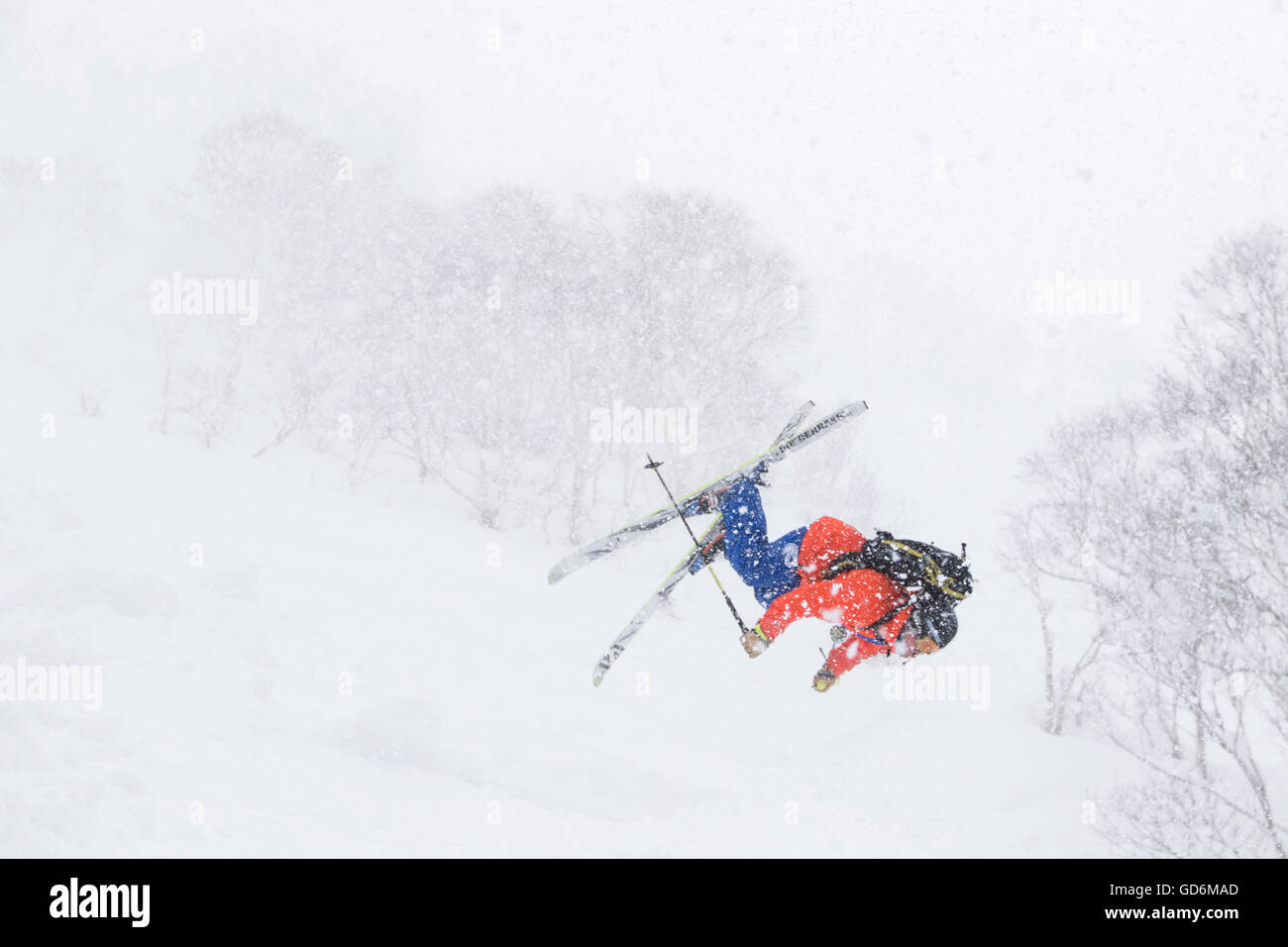 A male backcountry skier is flying upside down and head first in the ...