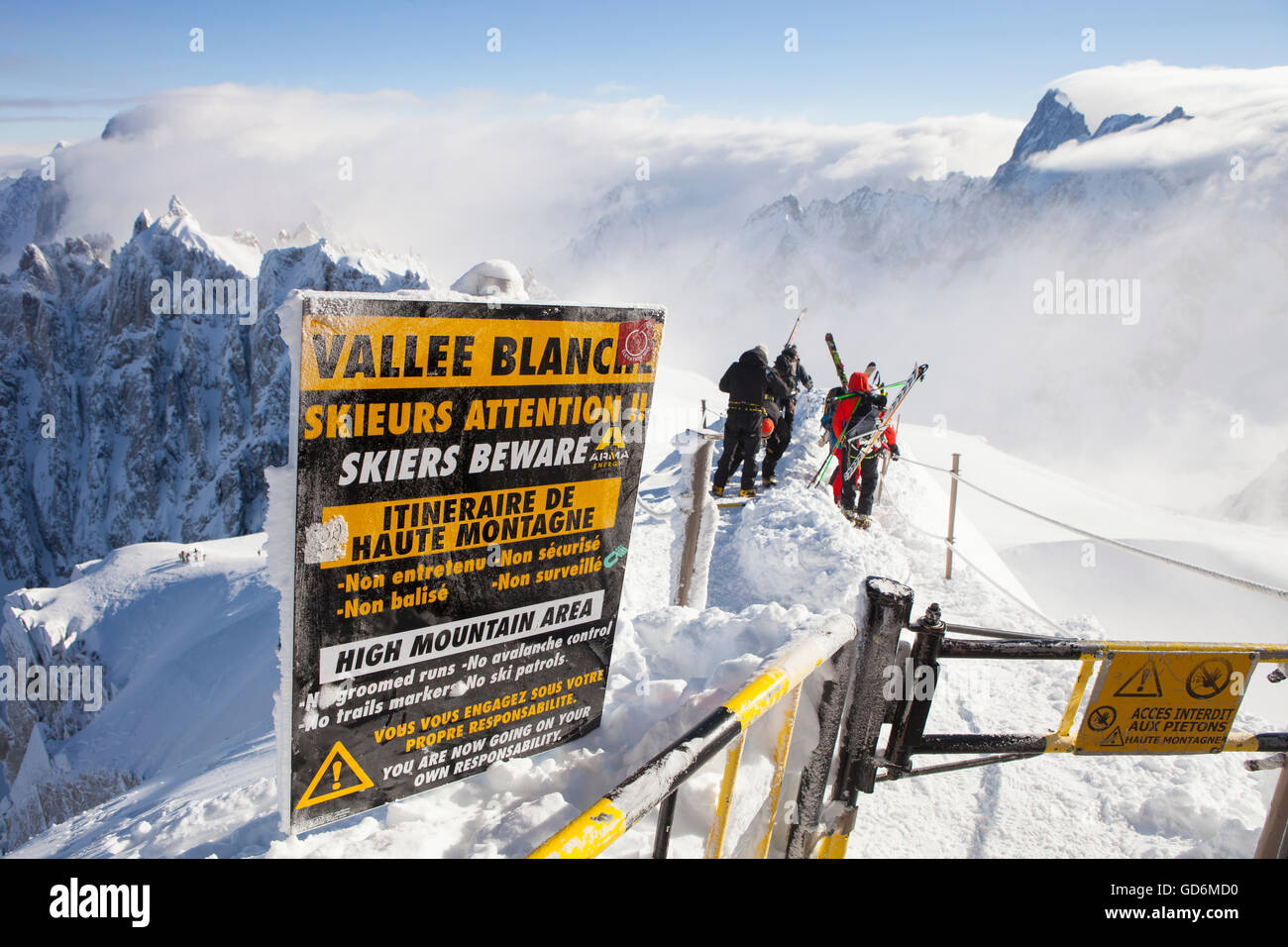 Skiers are walking down the mountain ridge from the peak of Aiguille du ...