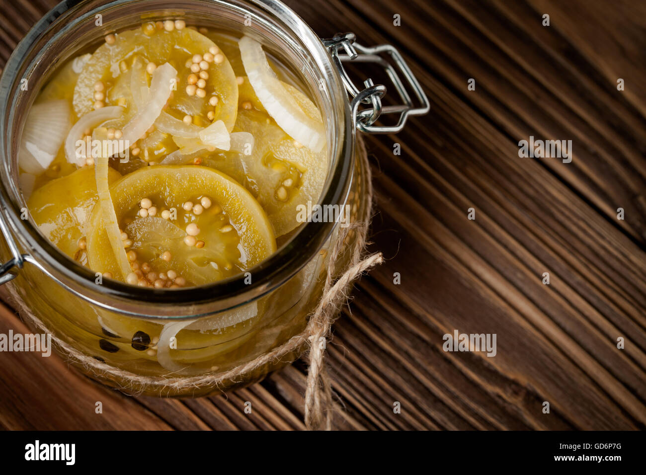 Homemade DIY natural marinated green tomatoes in a jar on wooden table ...