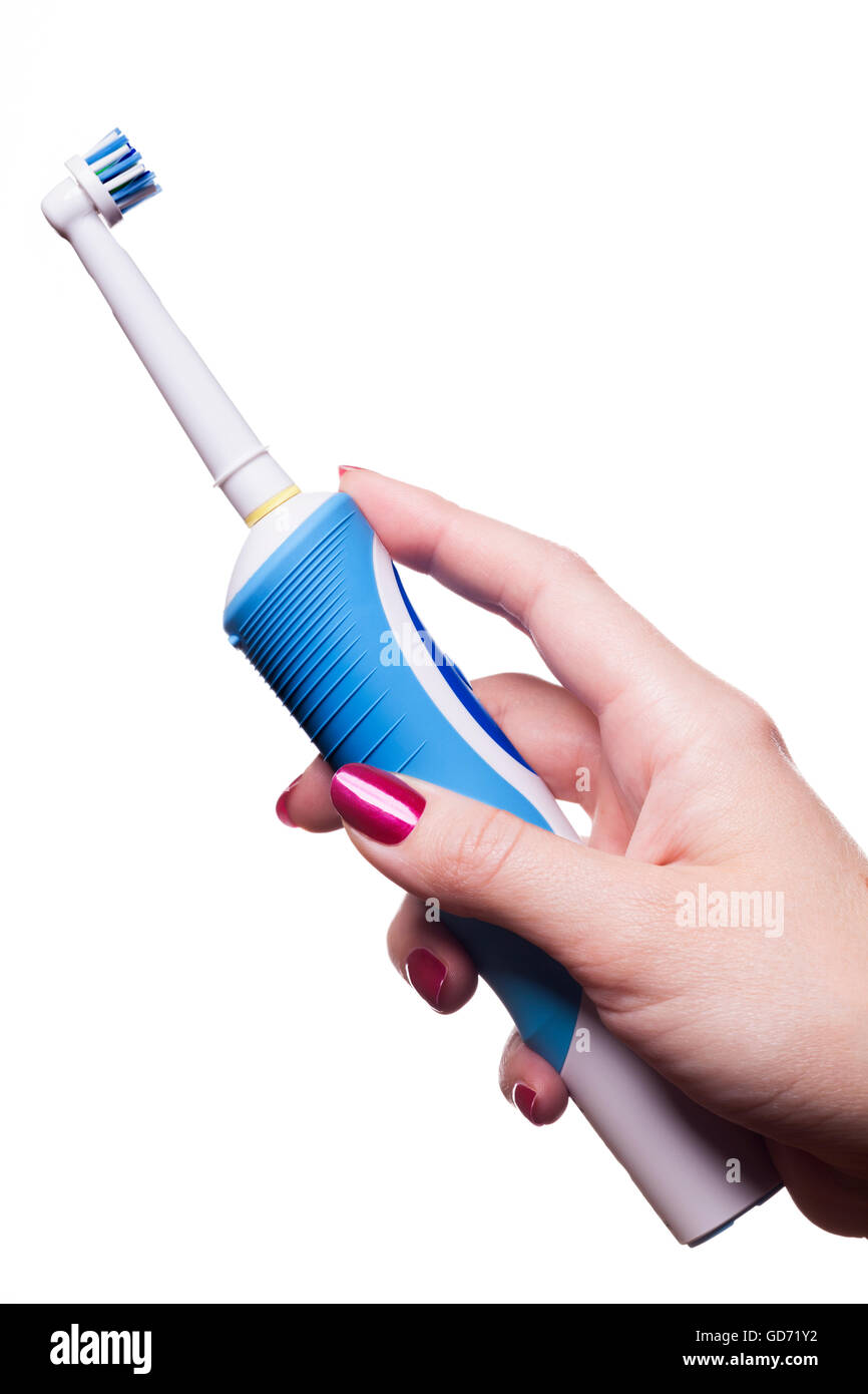 Hand with manicure holds single blue electric toothbrush against white ...