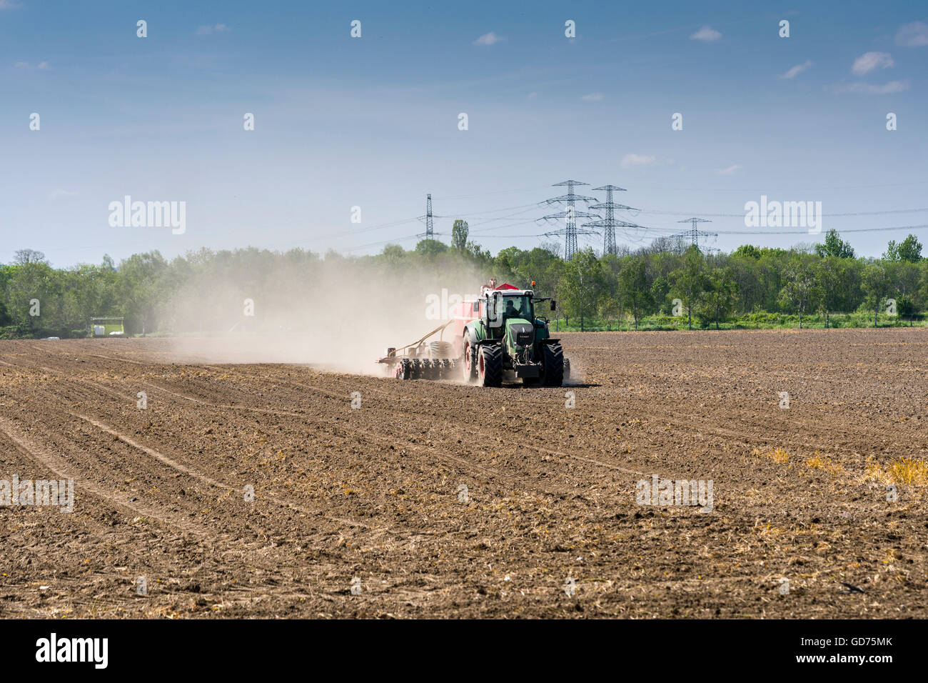 Agricultural landscape with a tractor ploughing a field, trees and ...