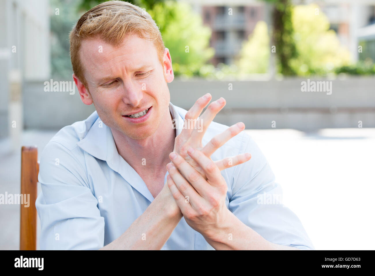 Closeup portrait, young man having acute bad joint pain in his hands ...
