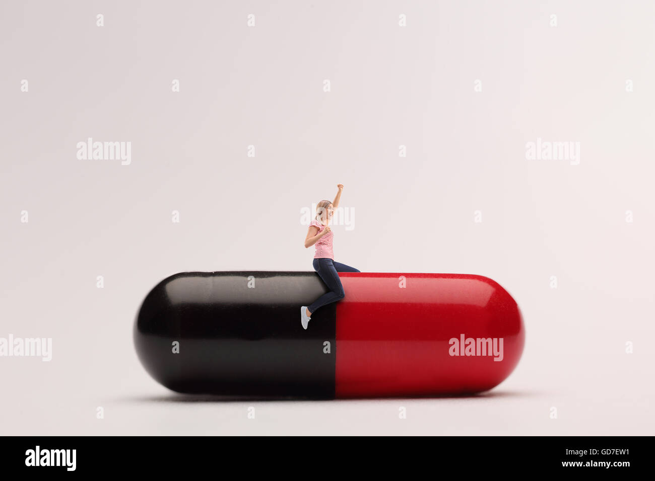 Delighted woman sitting on a giant pill and gesturing happiness Stock ...