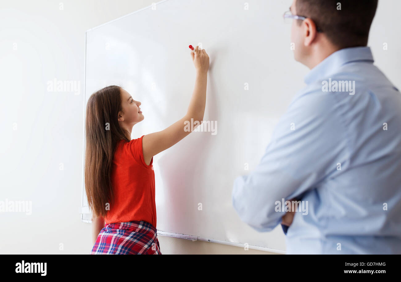 student writing on board and teacher at school Stock Photo - Alamy