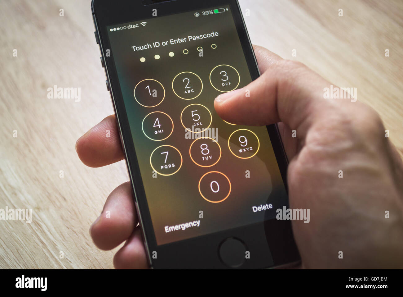 Apple iPhone5s held in one hand showing its screen with numpad for ...
