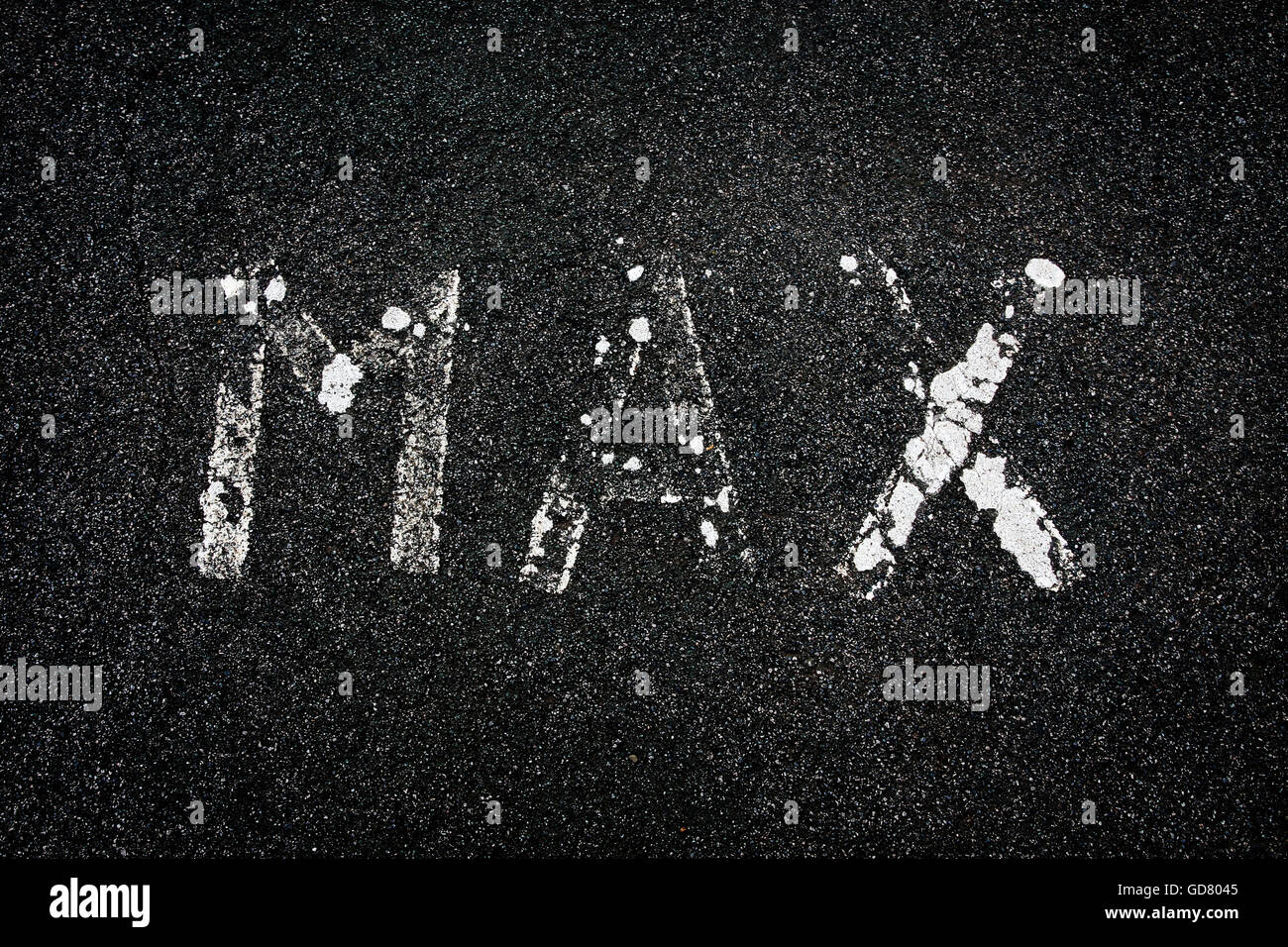 The word 'max', worn and faded, painted in white on a tarmac road Stock ...