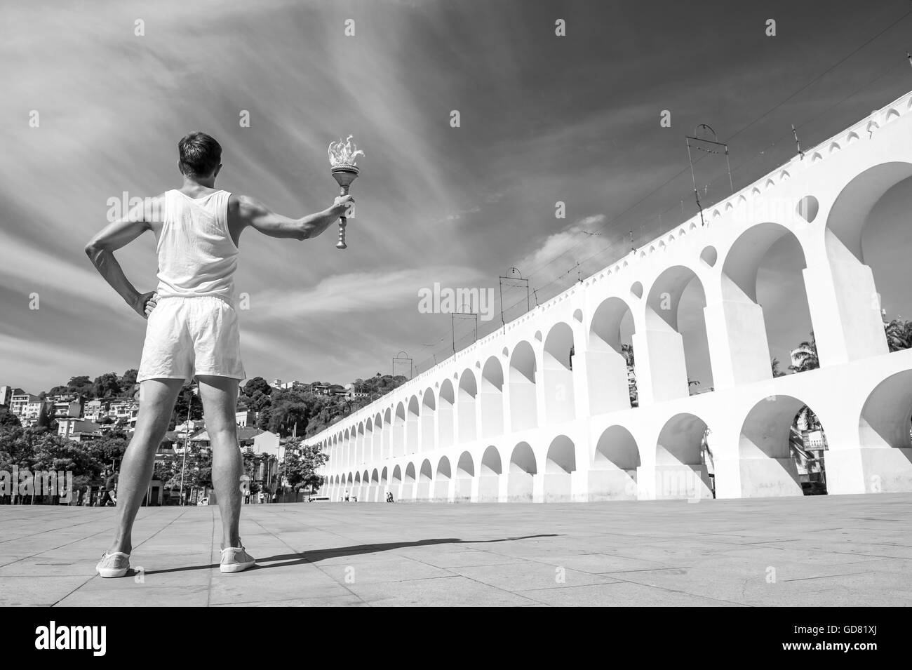 Torchbearer athlete standing with sport torch in front of the Arcos da ...