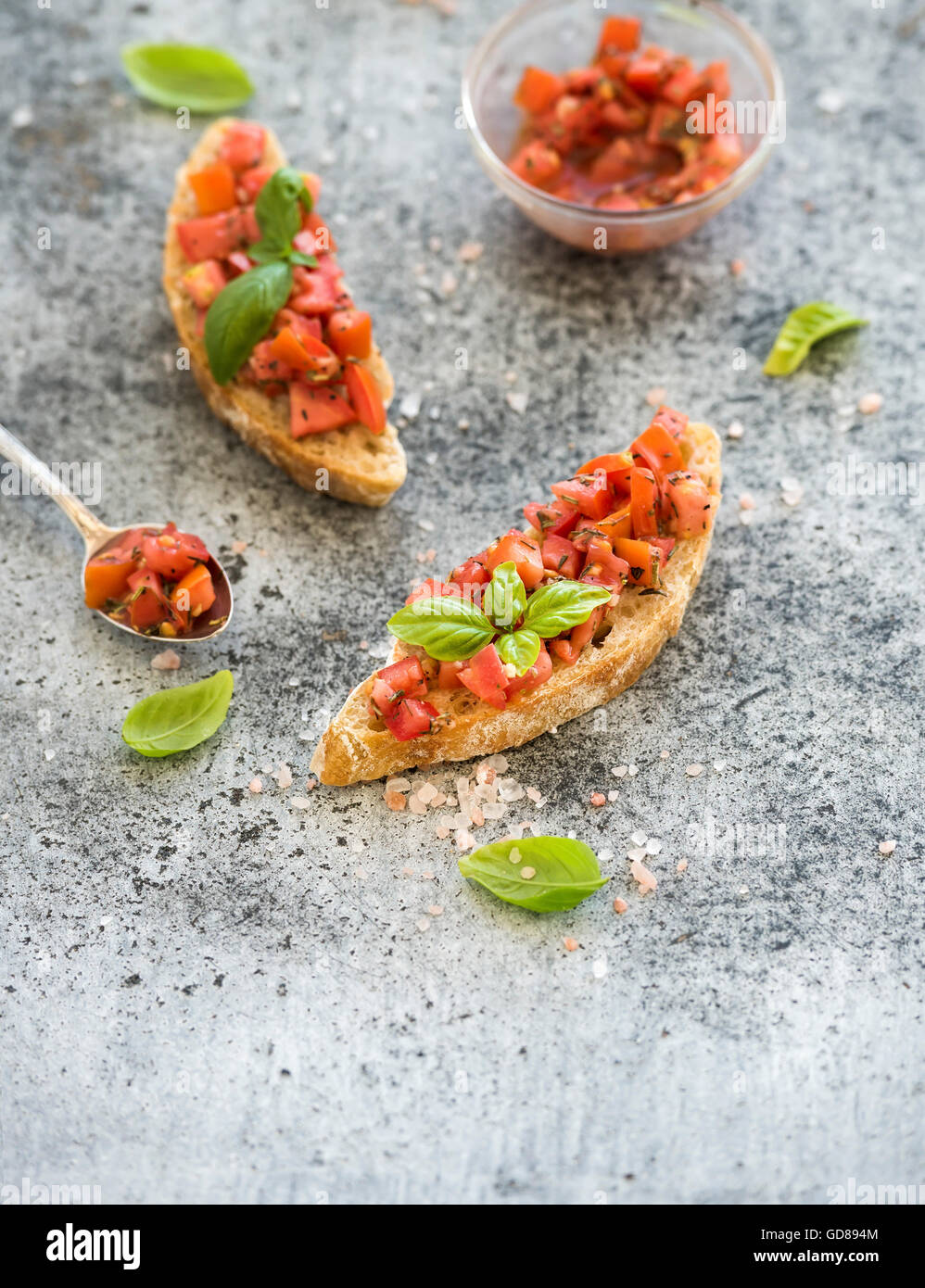 Two canapes with tomatoes and basil over concrete background, top view ...