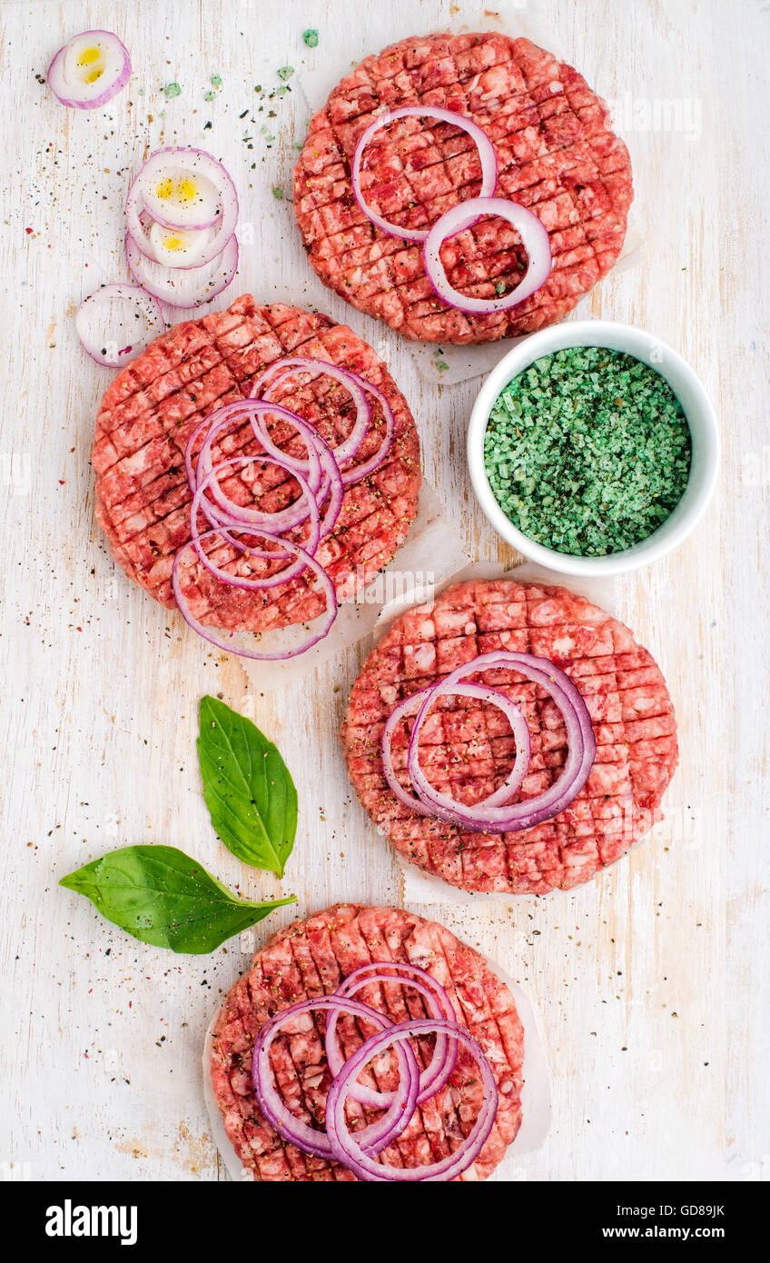 Raw beef meat cutlet for making burgers with onion rings and spices on ...