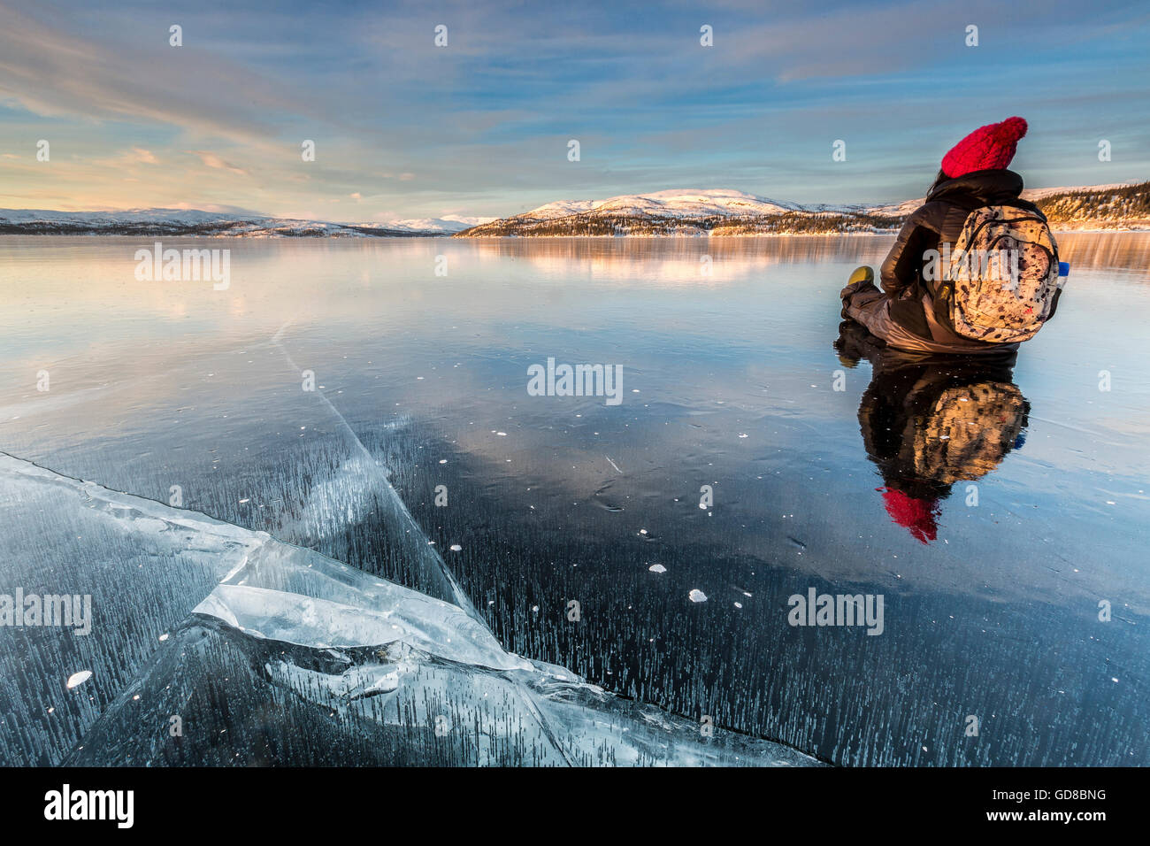 Hiker admires the landscape from the frozen surface of Lake Limingen ...