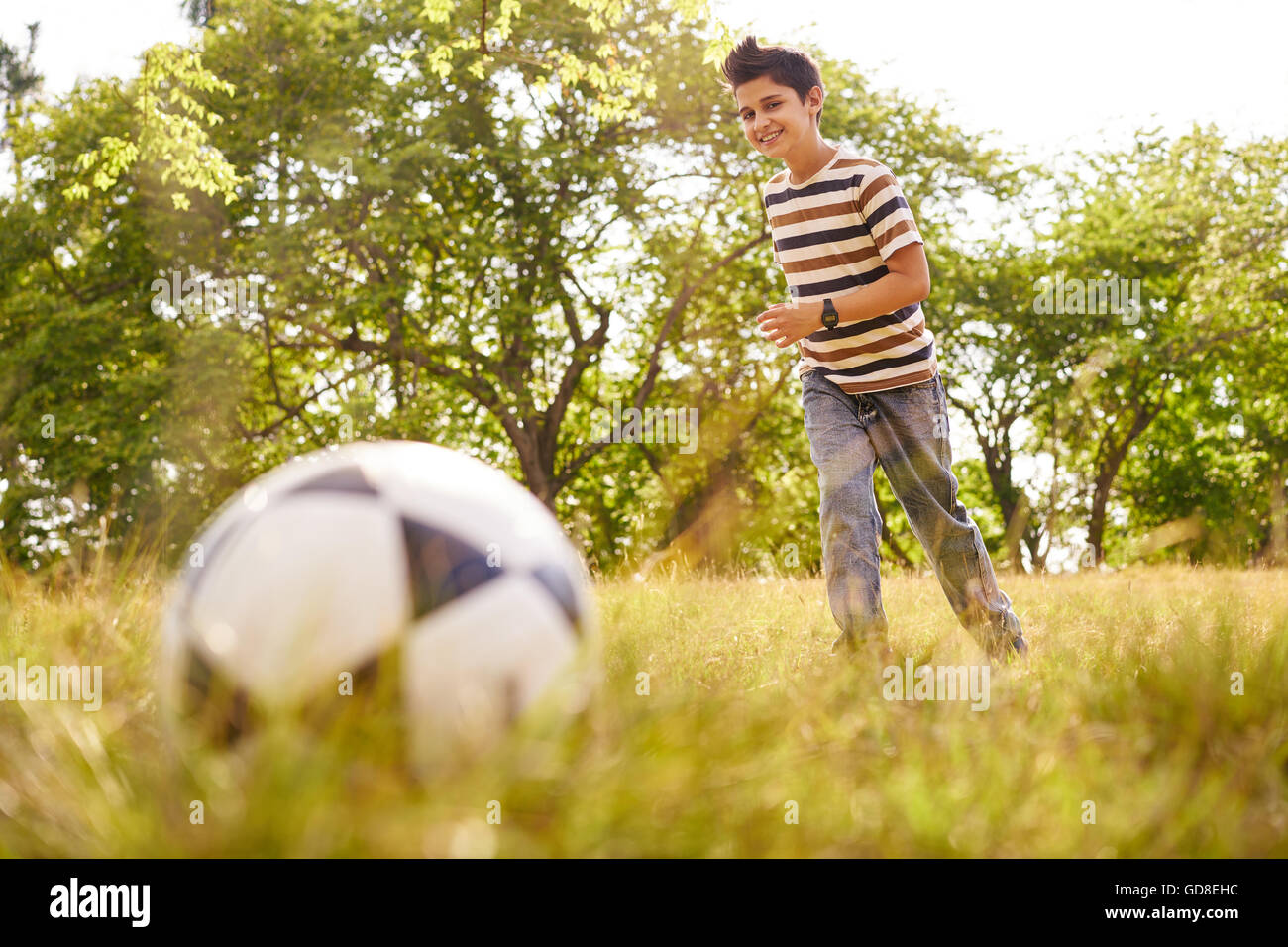 Adolescence and leisure activity. Young kid playing soccer in park ...