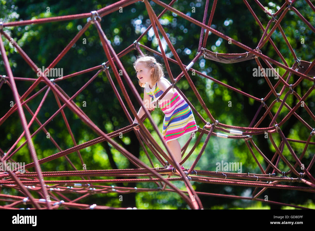 Active little child playing on climbing net and jumping on trampoline ...