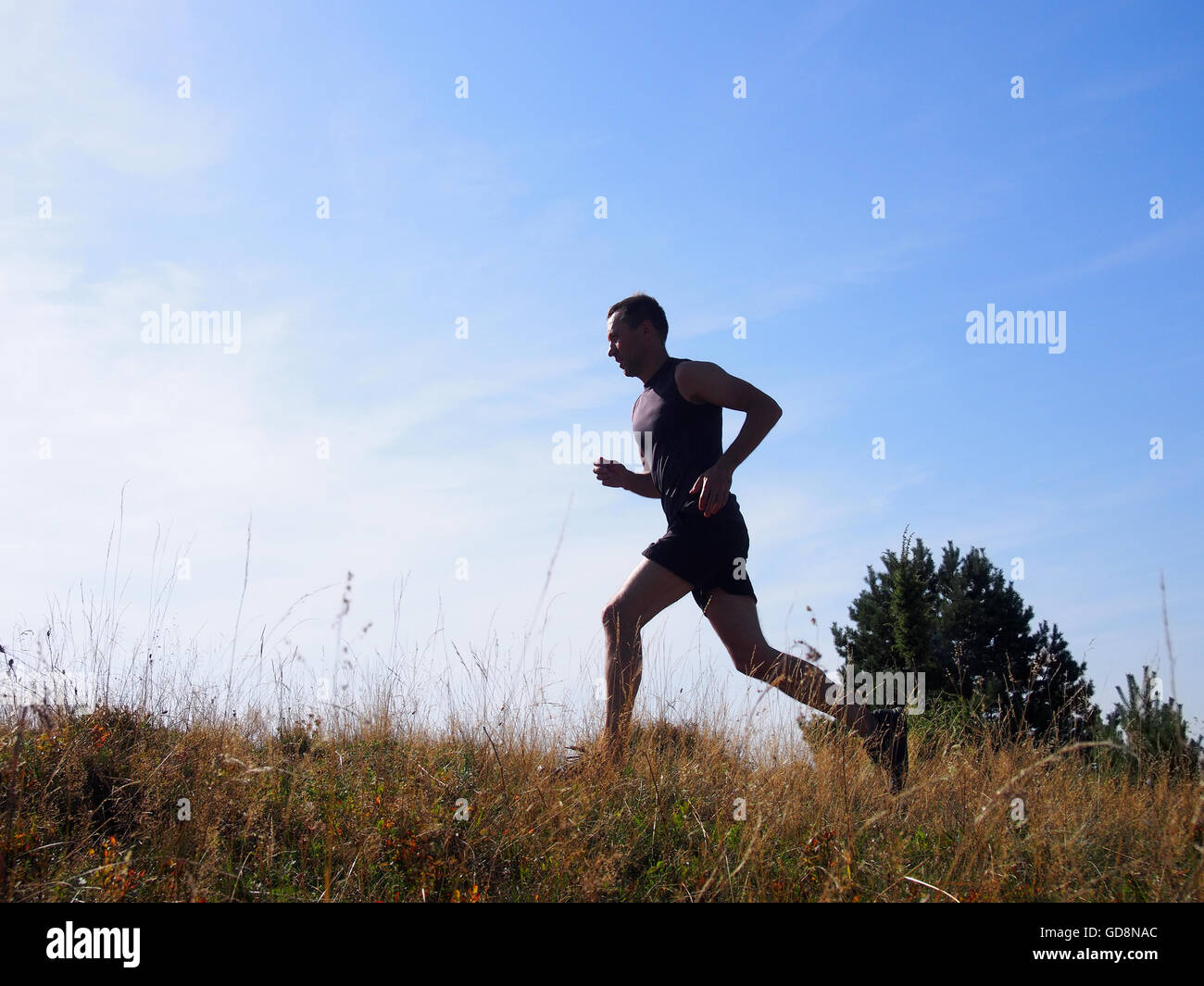 Mountain runner running at blue sky background Stock Photo - Alamy