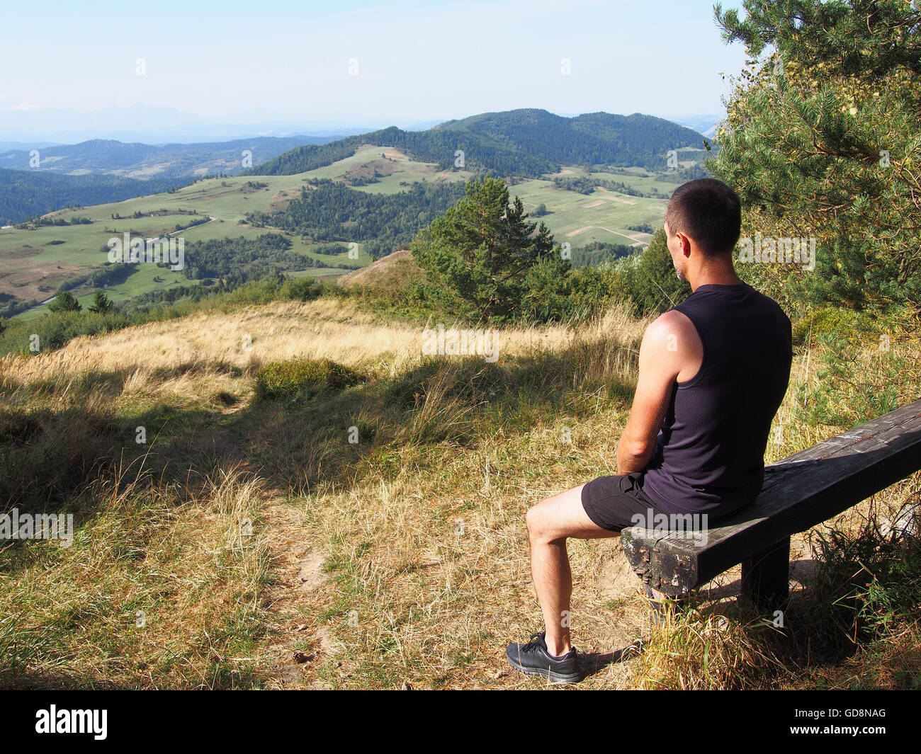 Runner athlete sitting on bench and resting in mountains, looking into ...
