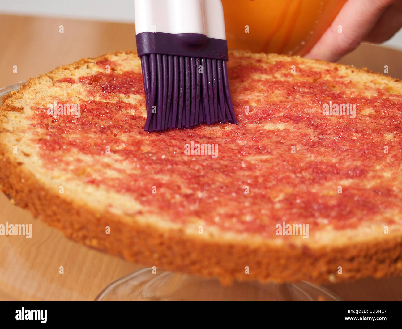 Spreading cake layer with jam. Making torte with buttercream filling ...