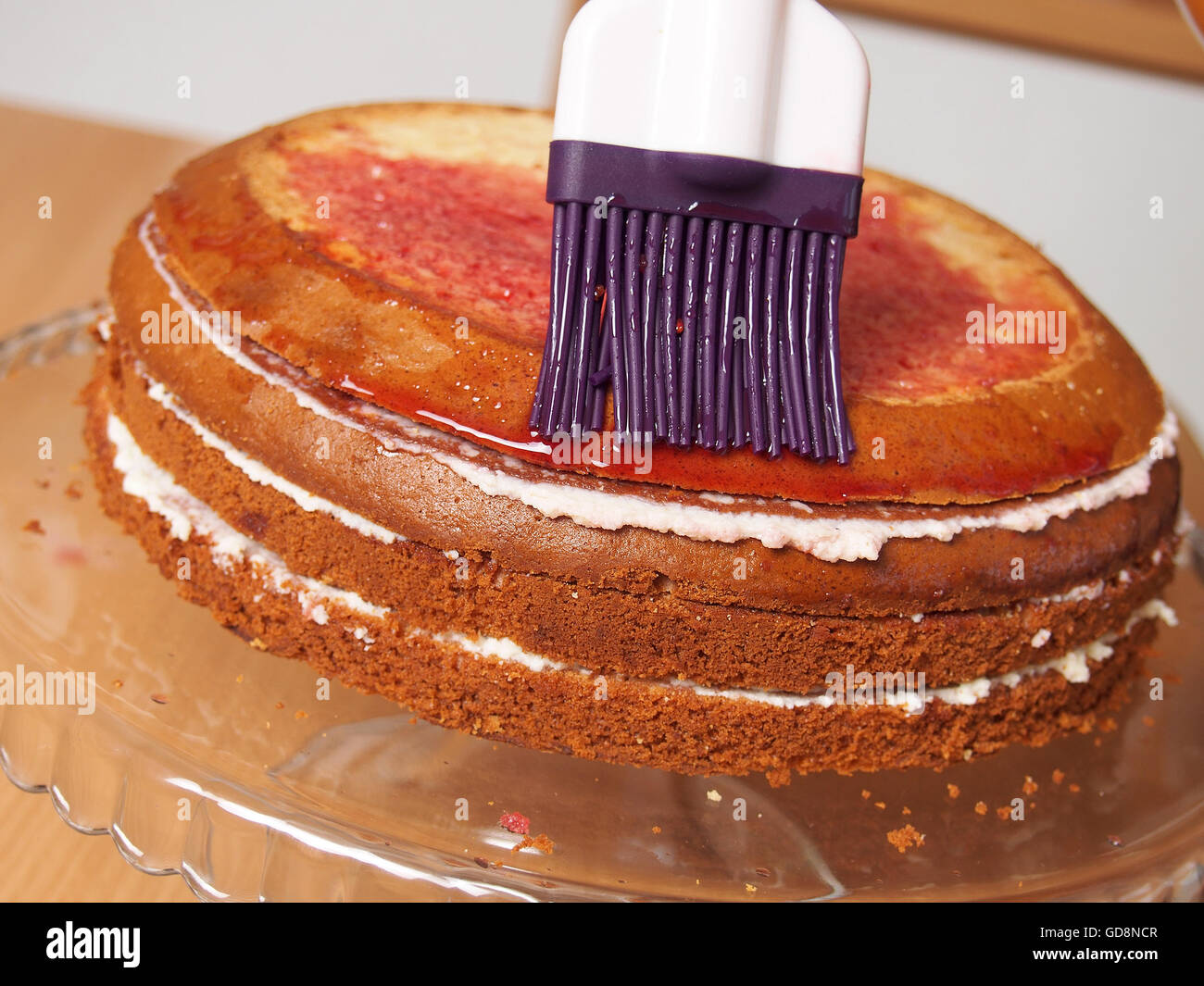 Spreading cake layer with jam. Making torte with buttercream filling ...