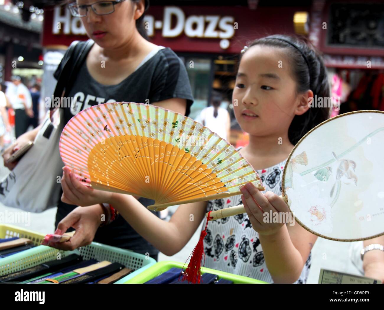 Shanghai. 13th July, 2016. A girl chooses fans during a cultural ...